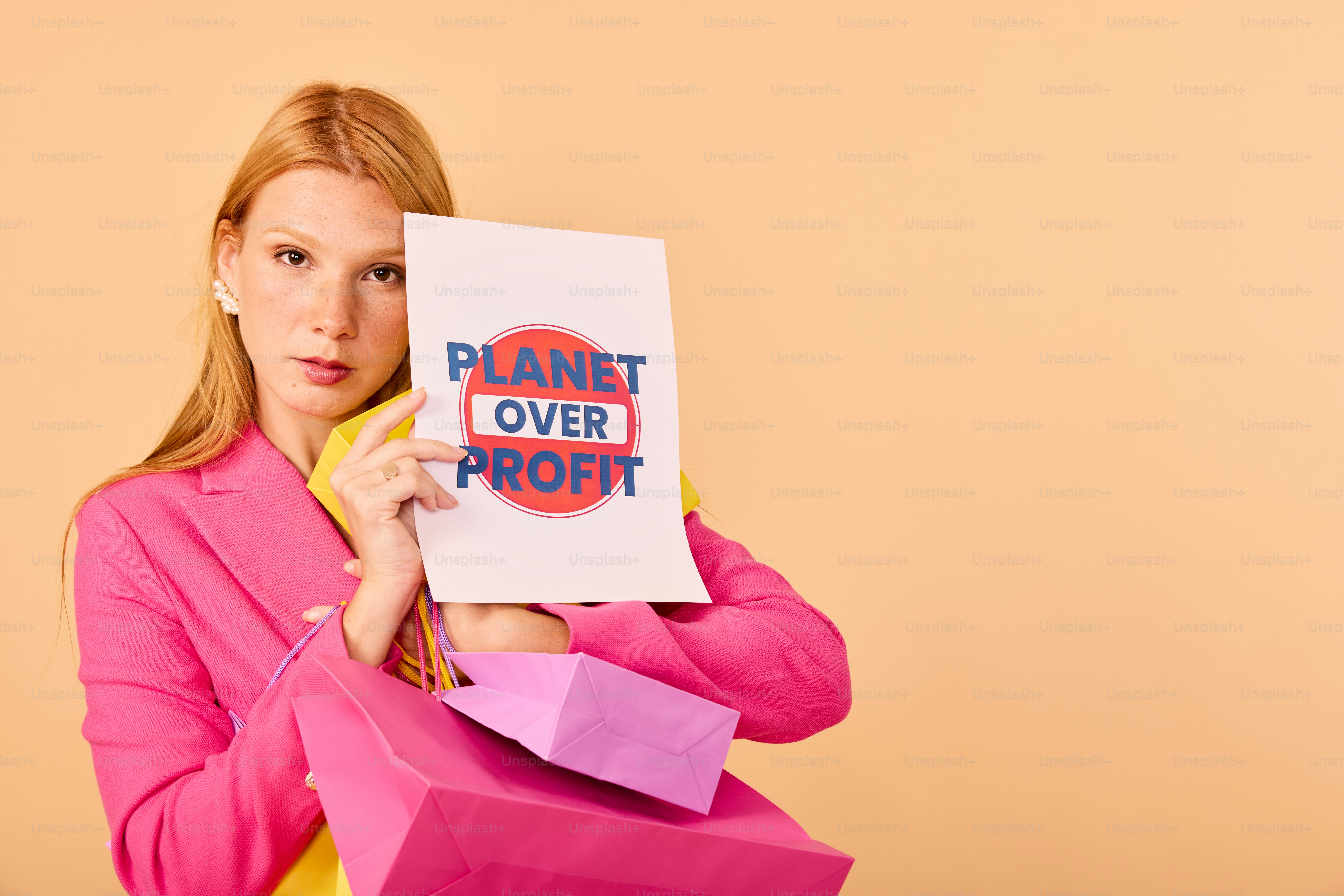 A woman holding a sign that says planet over profits photo – Poster Image on Unsplash