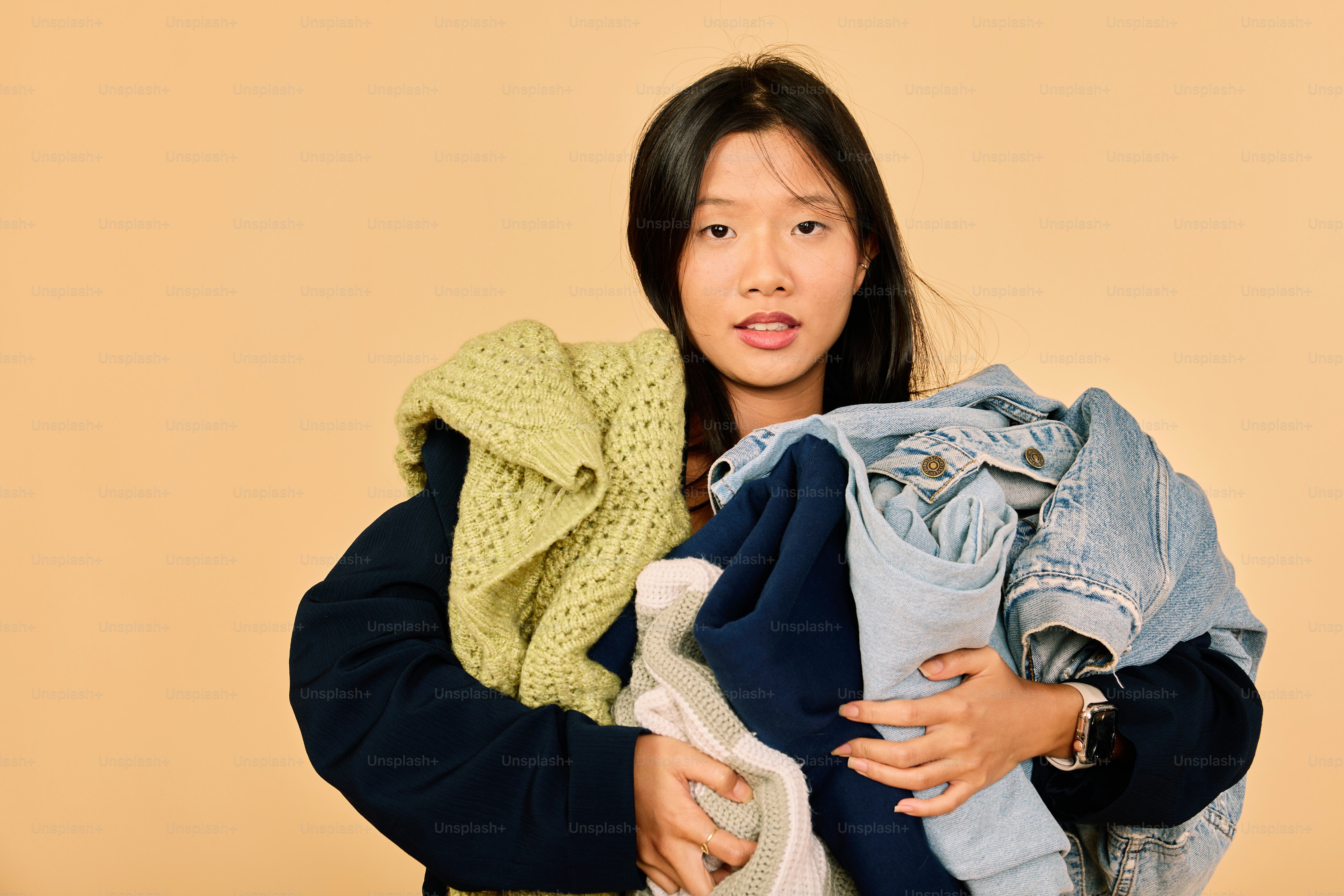 A woman holding a pile of clothes in her hands photo – Consumerism ...