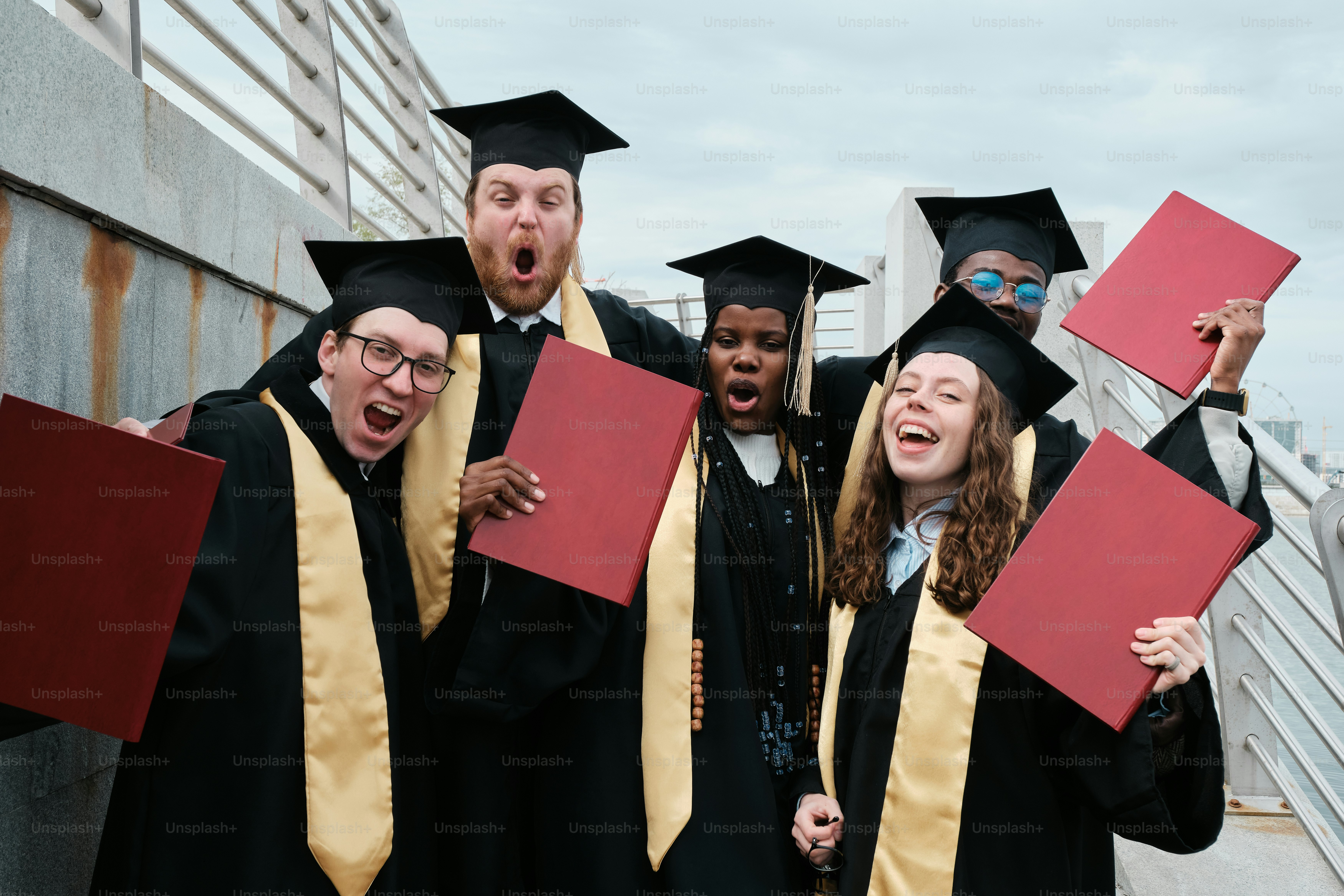 A group of people in graduation gowns holding red folders photo ...