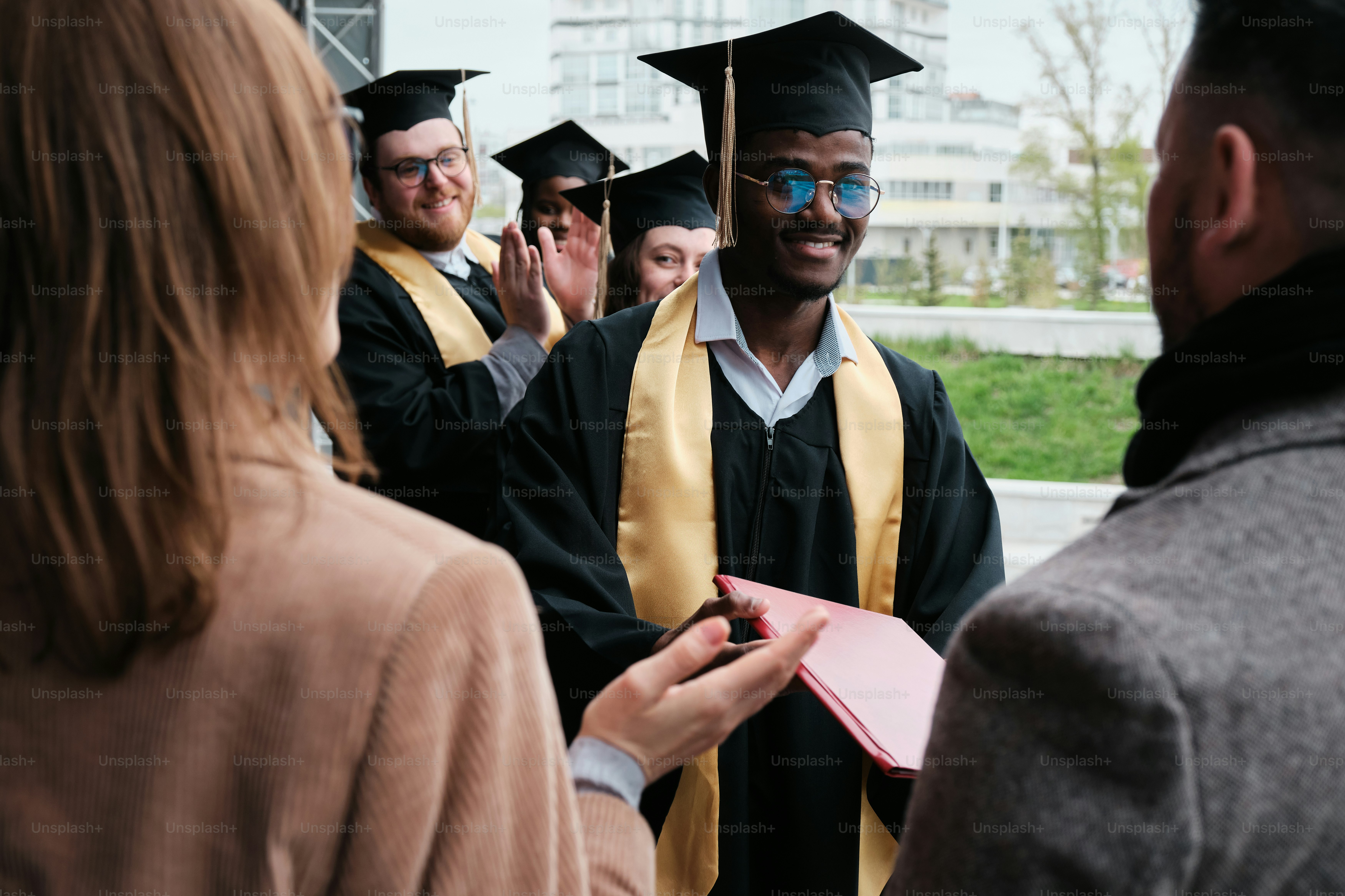 A group of people standing around each other wearing graduation caps ...