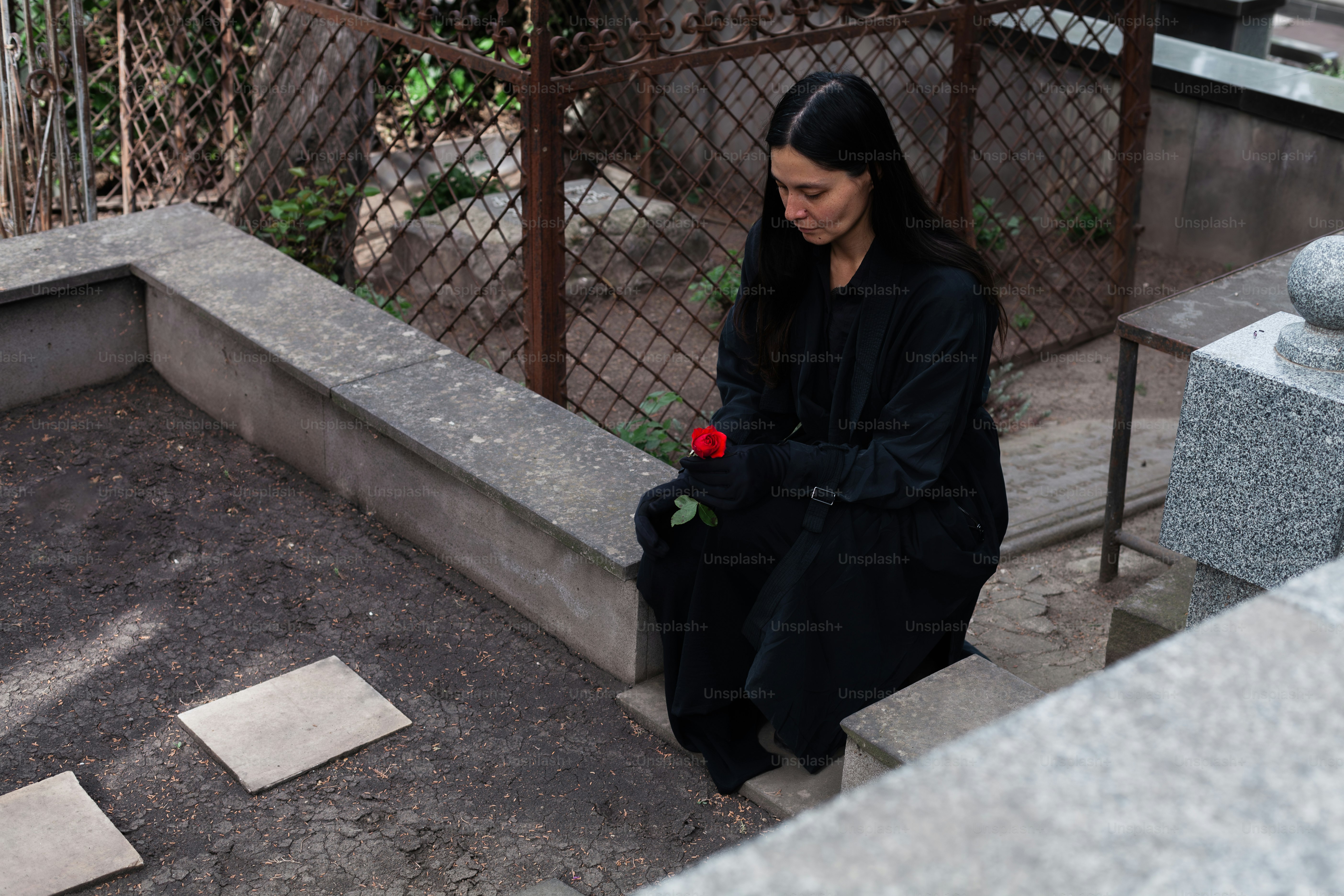 A woman sitting on a ledge with a rose in her hand photo – Graveyard ...