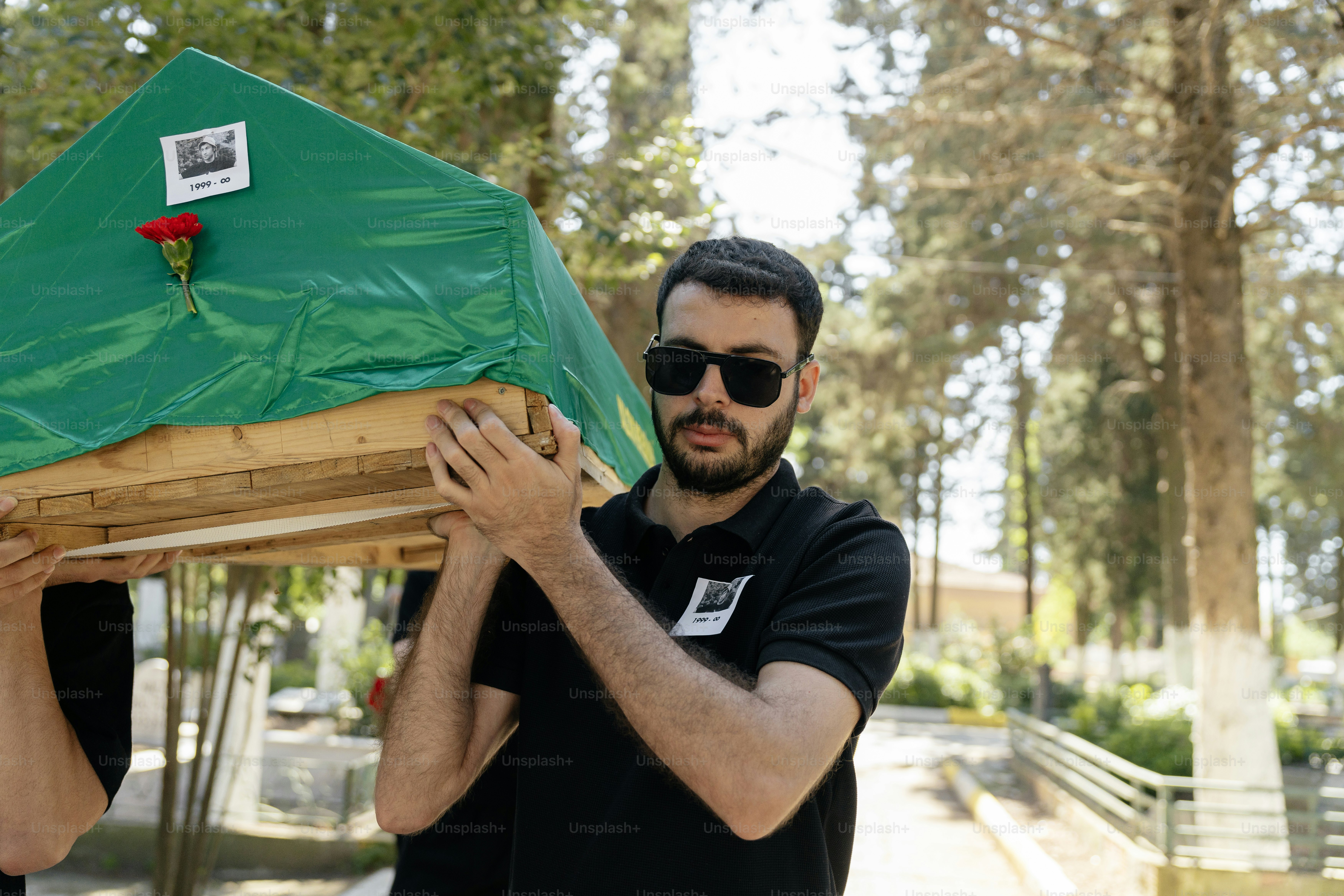 A man holding a wooden structure with a green tarp covering it photo ...