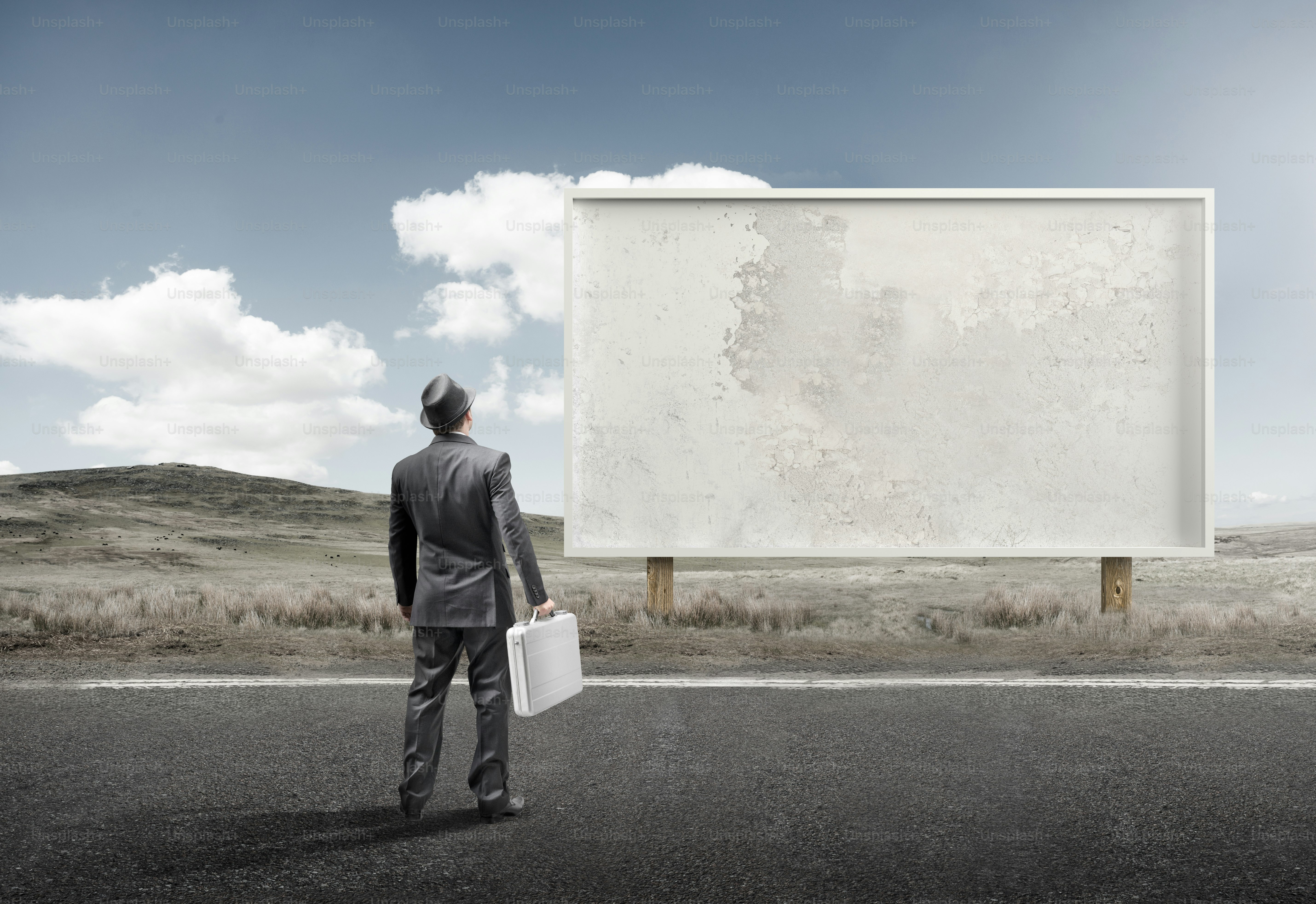 A business man standing and staring at a blank billboard advertisement ...