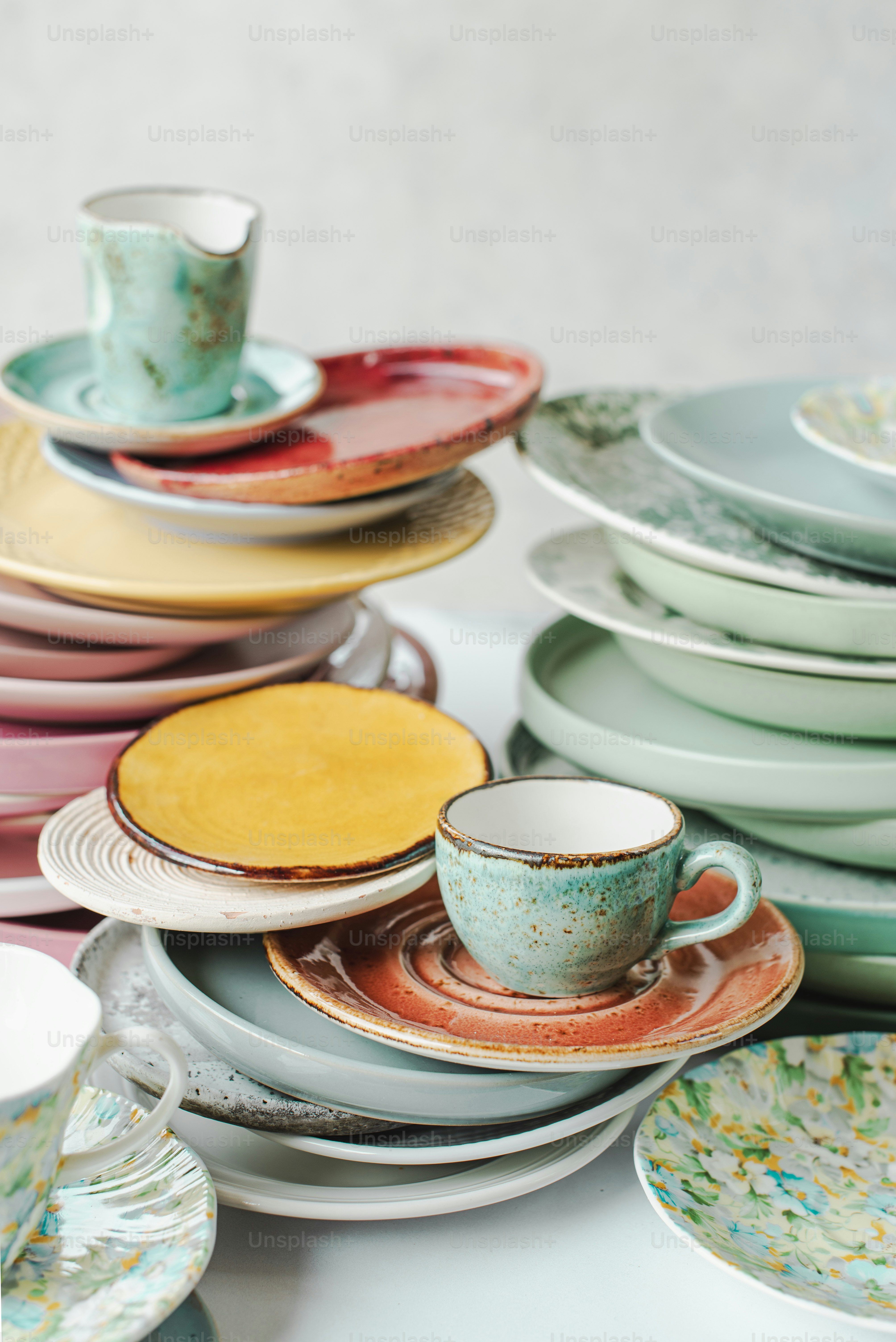 A table topped with lots of colorful plates and cups photo – Green ...