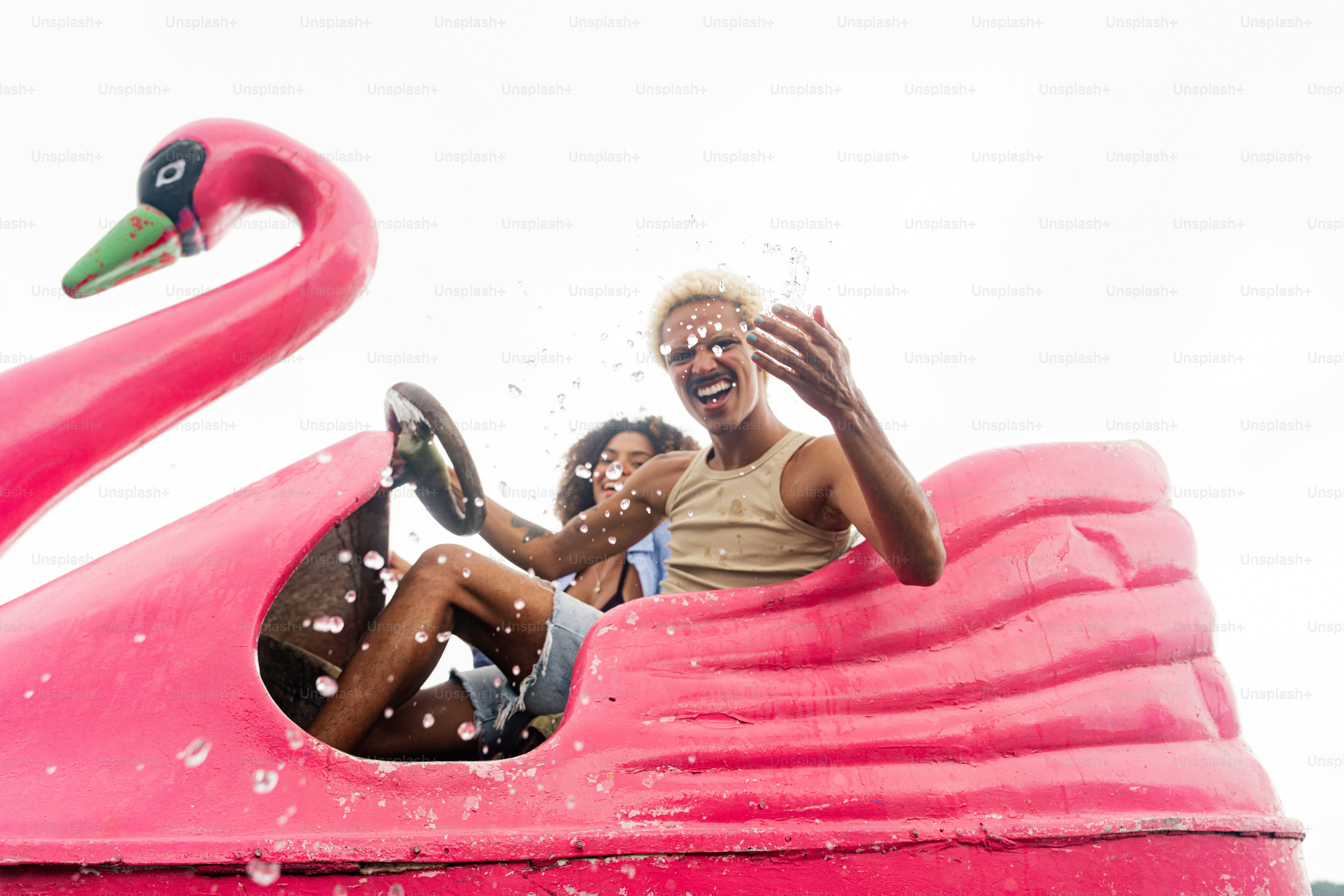 A couple of people riding a pink flamingo ride photo – Summer Image on ...
