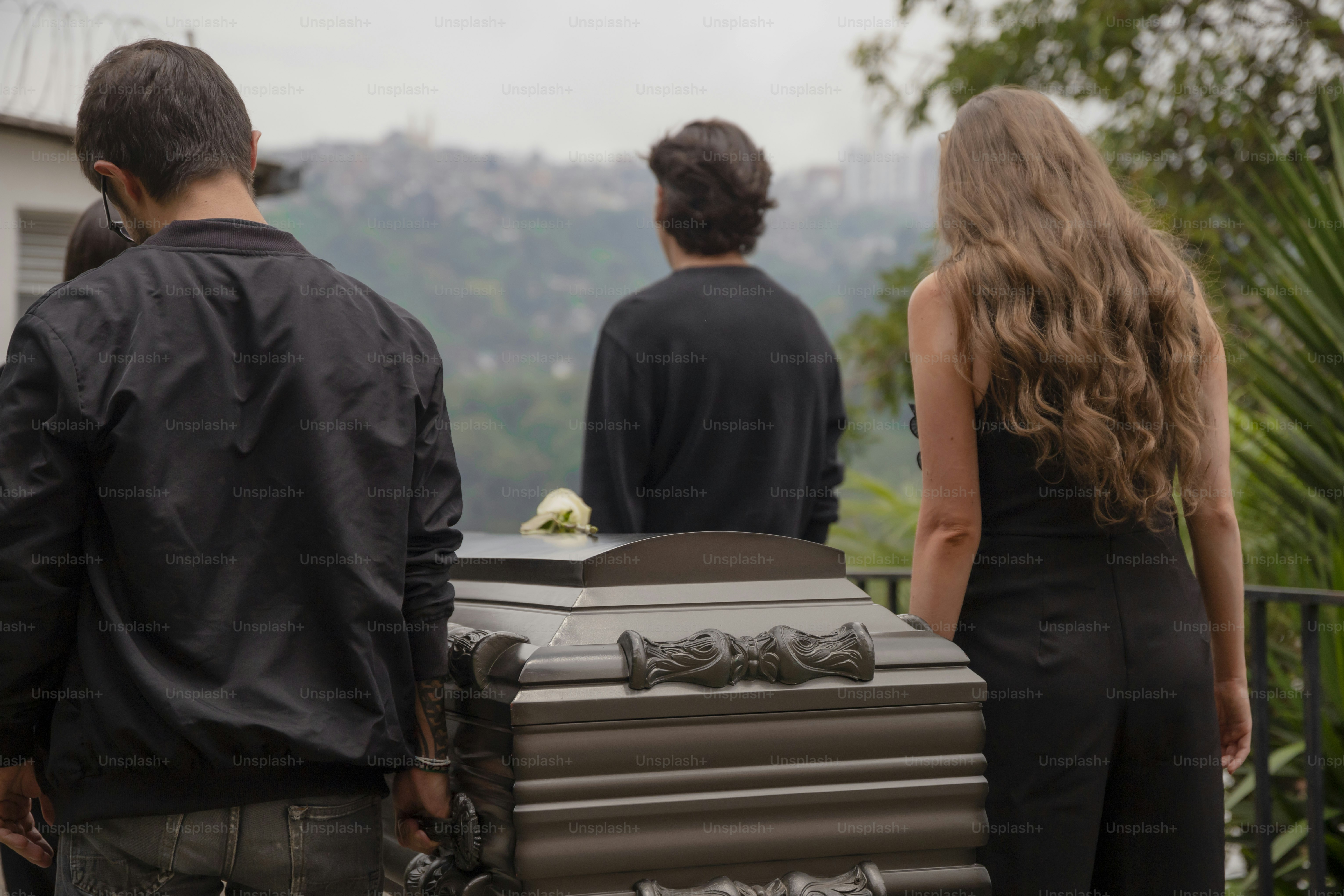 A group of people standing around a casket photo – Funeral service ...