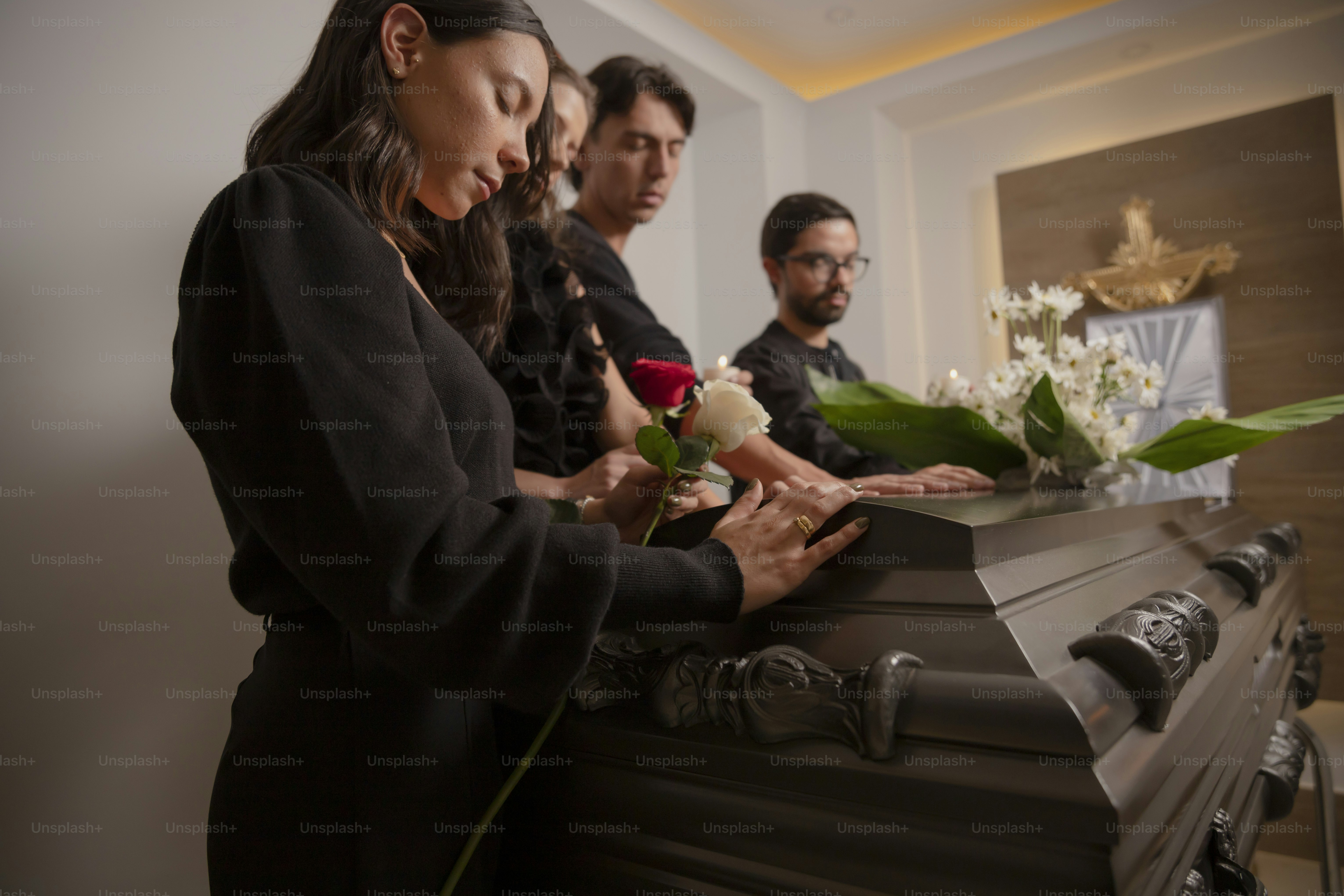 A group of people standing around a casket photo – Funeral service ...