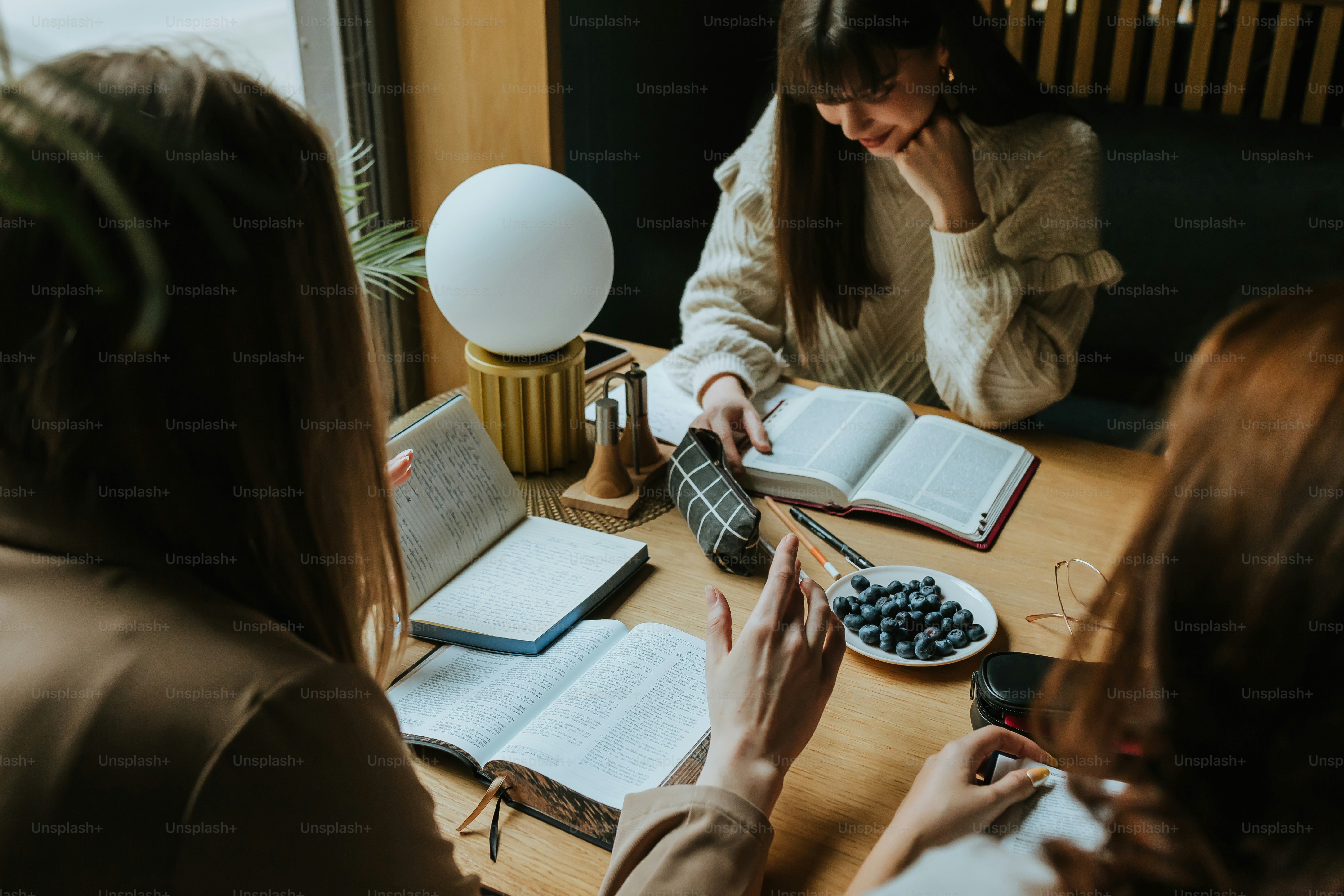 A group of women sitting around a table with books photo – Spiritual ...