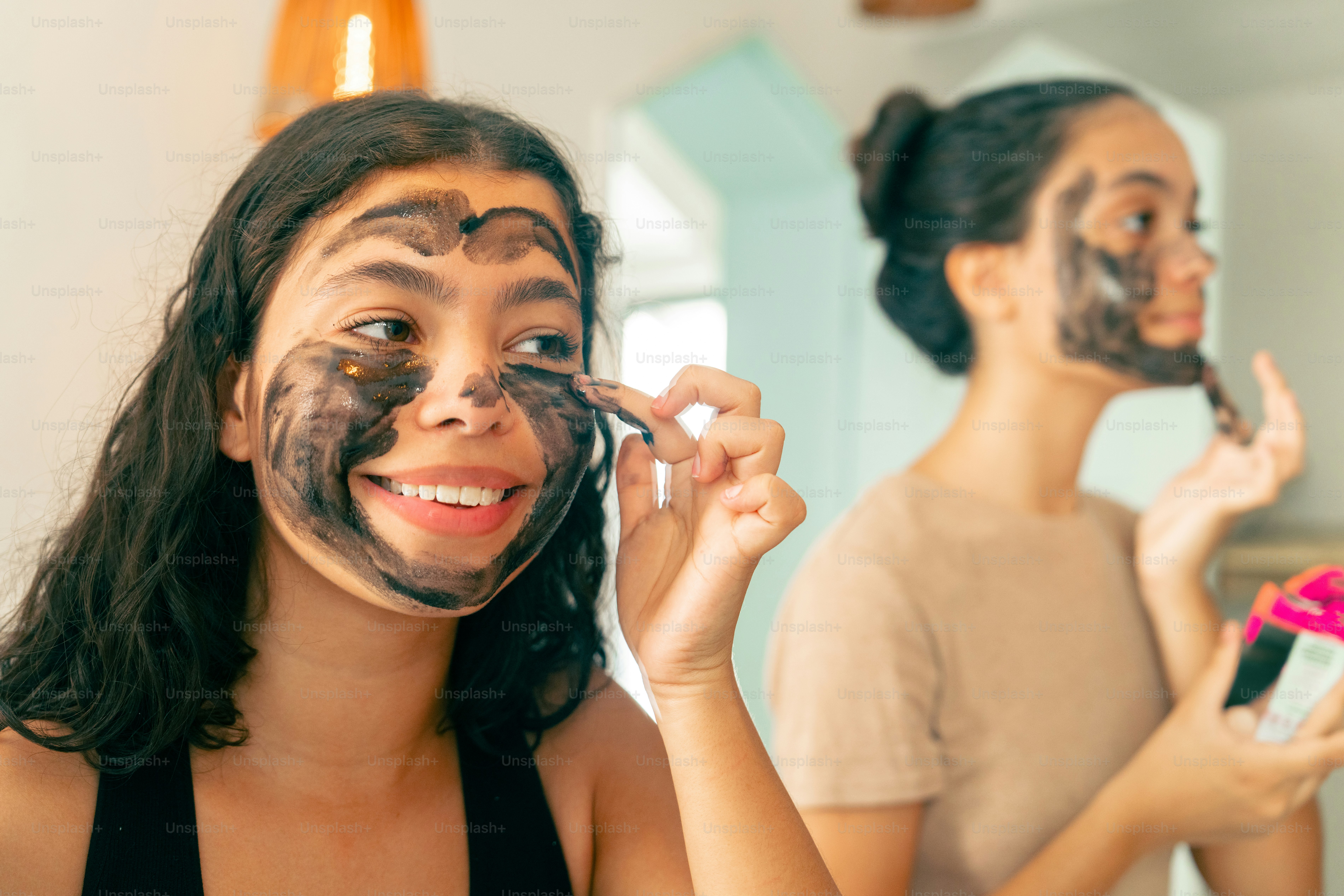 A woman is putting a face mask on her face photo – Beauty routine Image ...