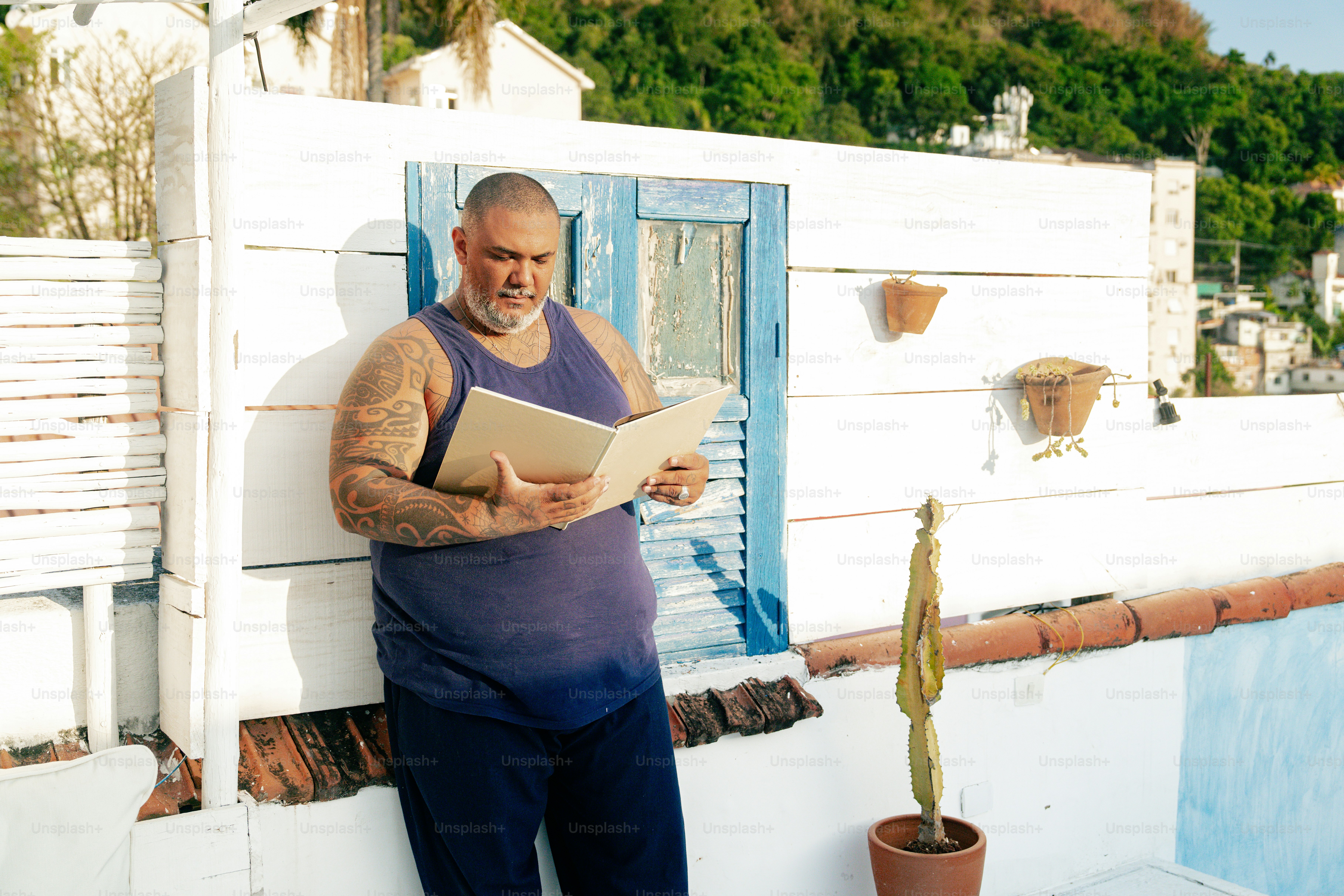 A man reading a book while leaning against a wall photo – Portrait ...
