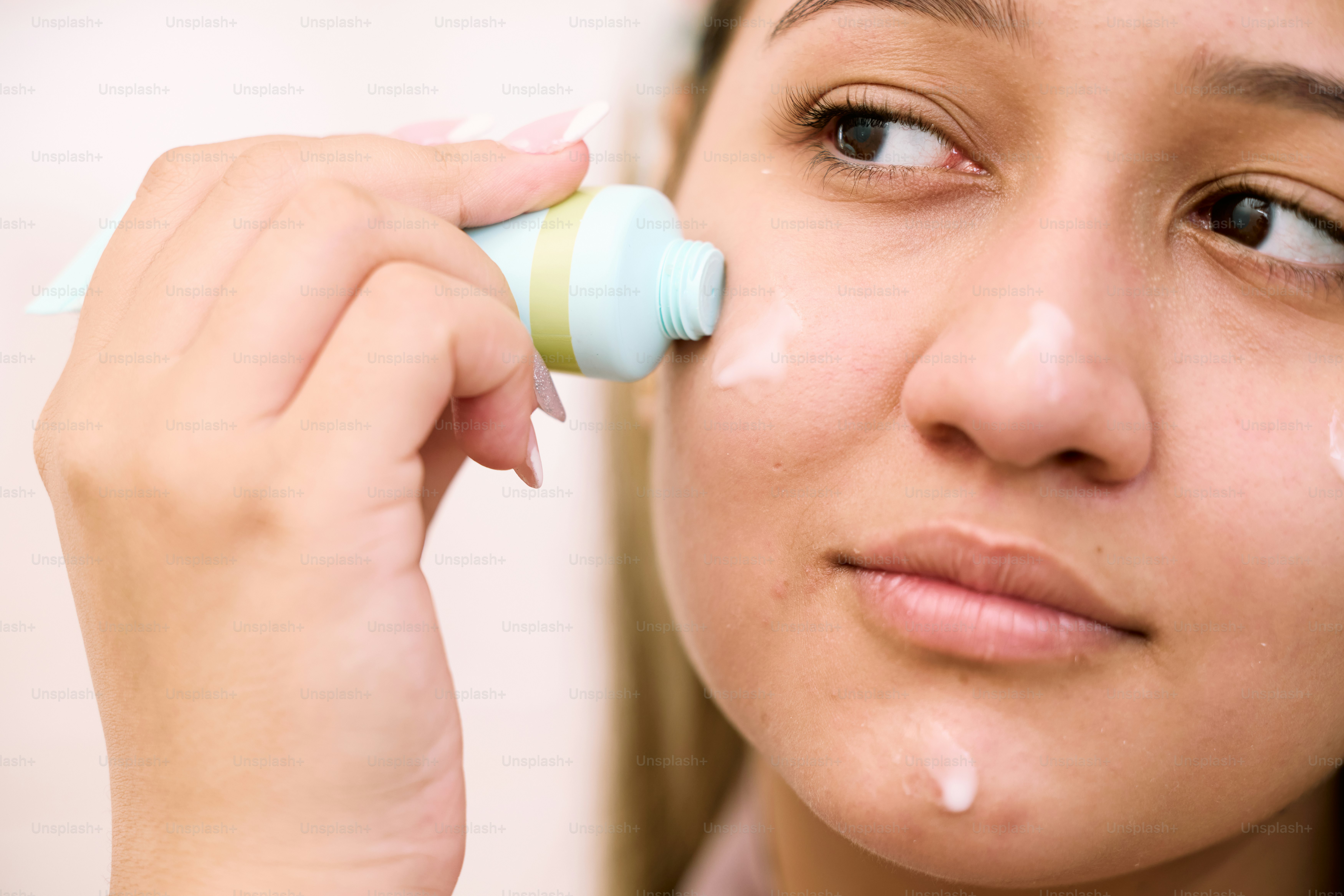 A woman is applying a lotion on her face photo – Moisturizer Image on ...