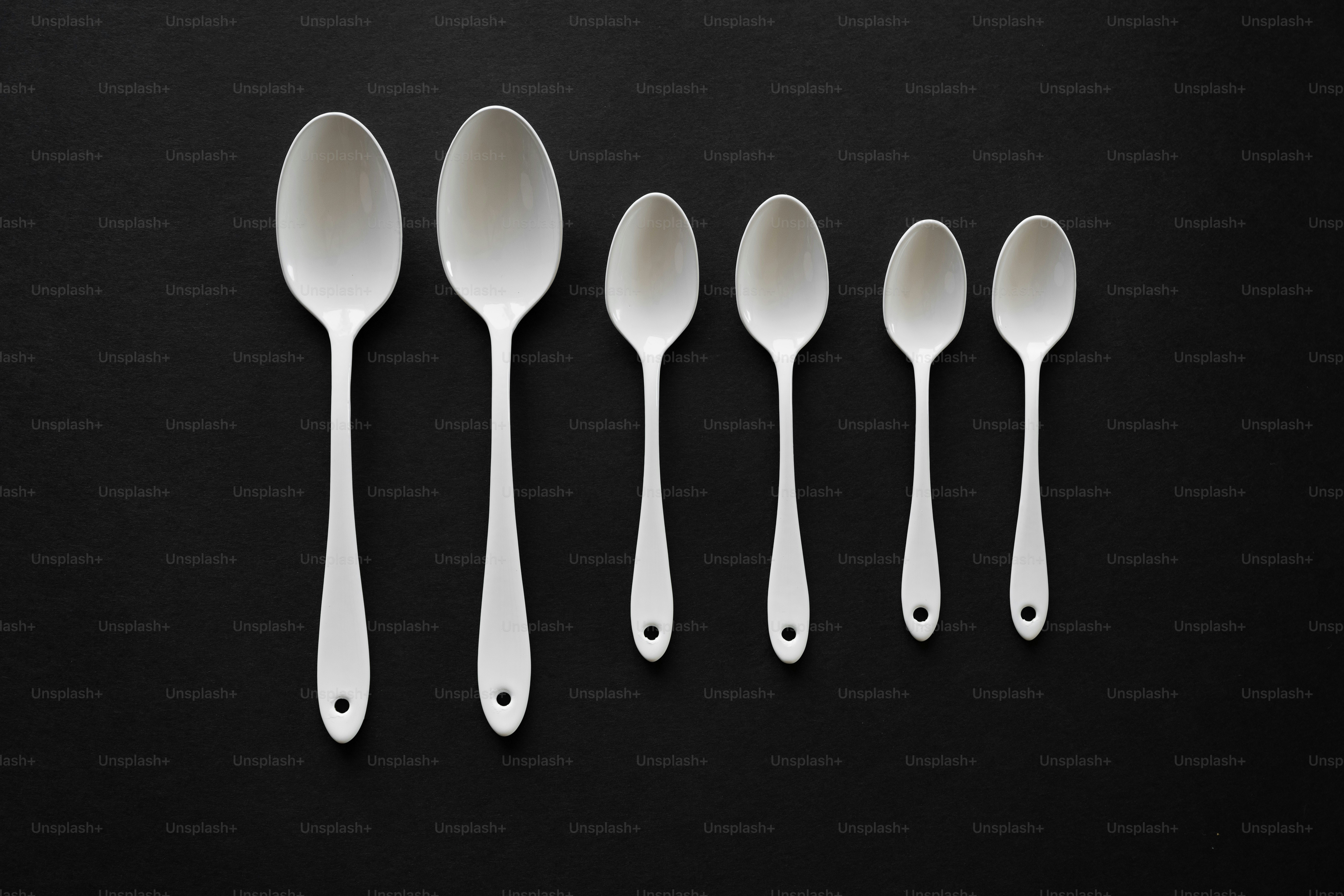 Six spoons lined up in a row on a black surface photo – Cutlery Image ...