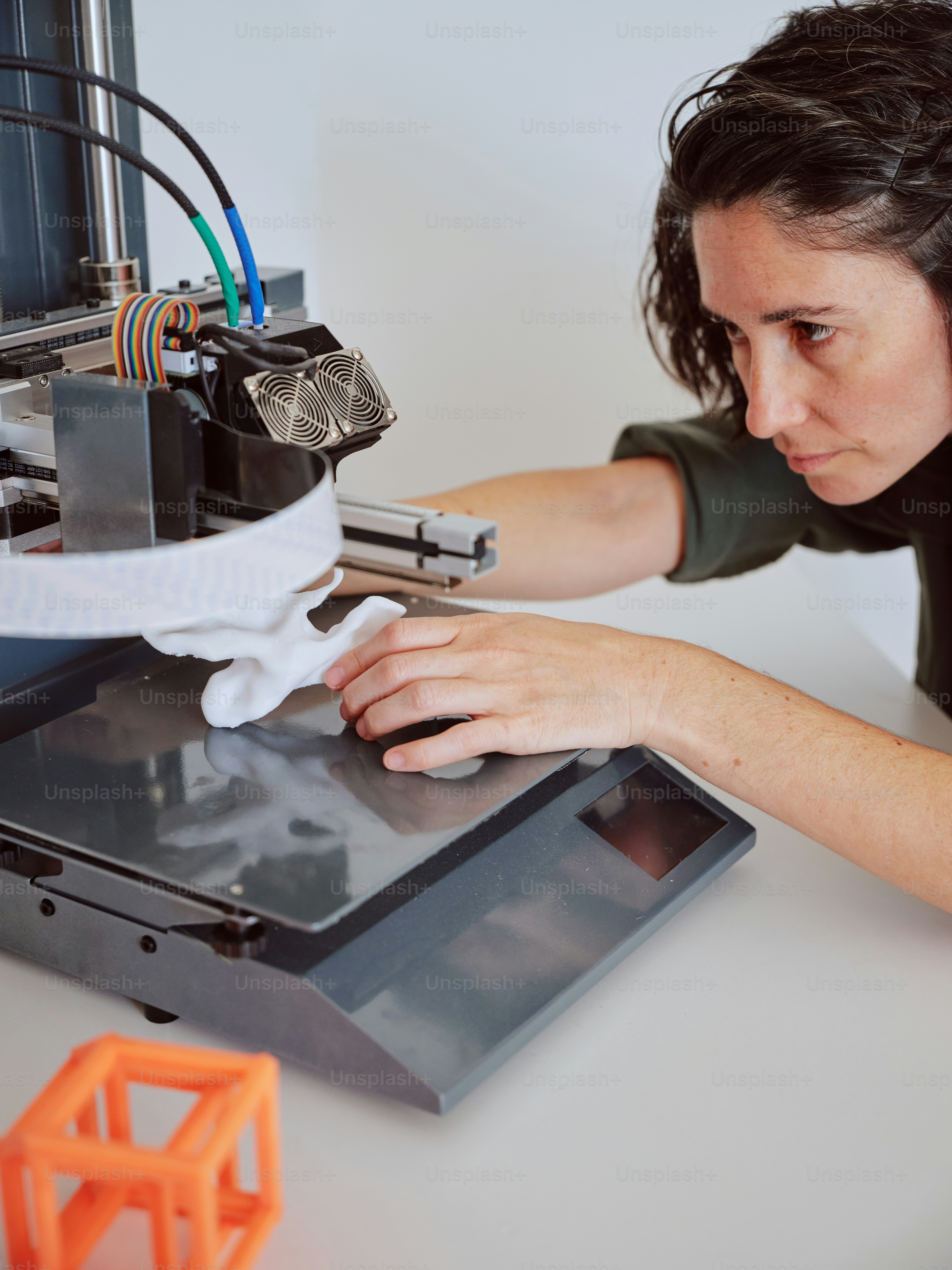A woman sitting at a table working on a 3d printer photo – 3d printing ...