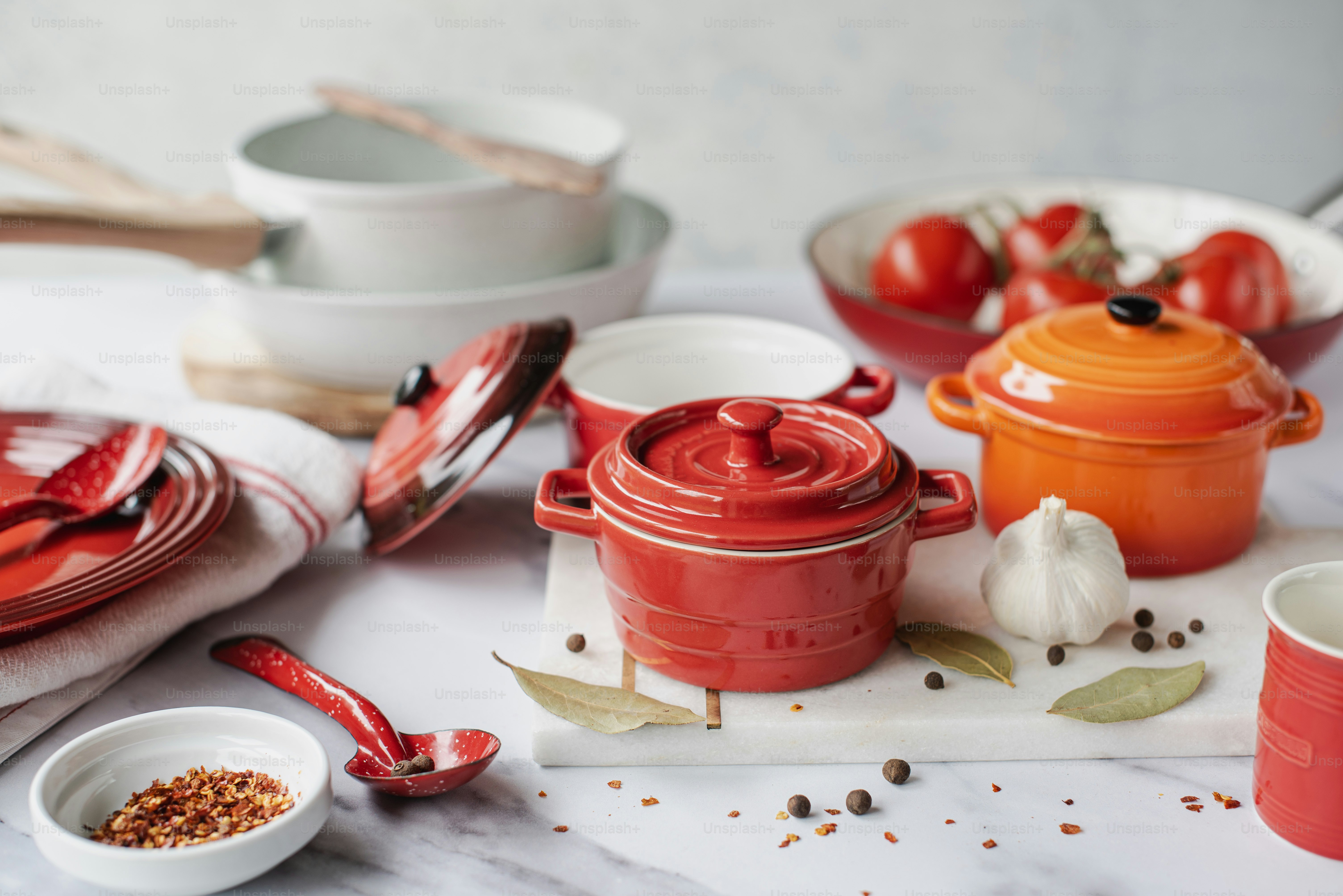 A table topped with red pots and bowls filled with food photo ...