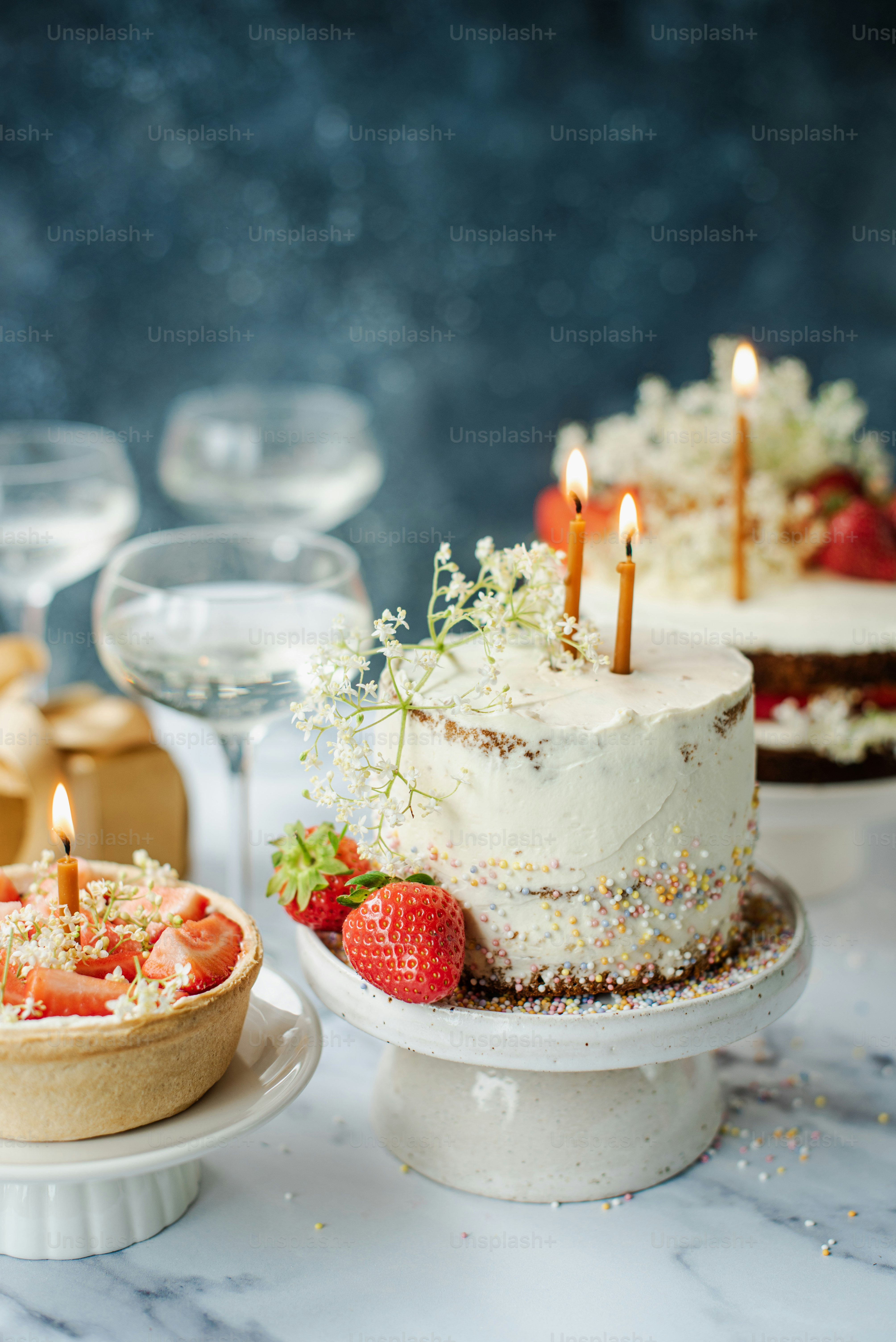 A table topped with three cakes covered in frosting photo – Strawberry ...