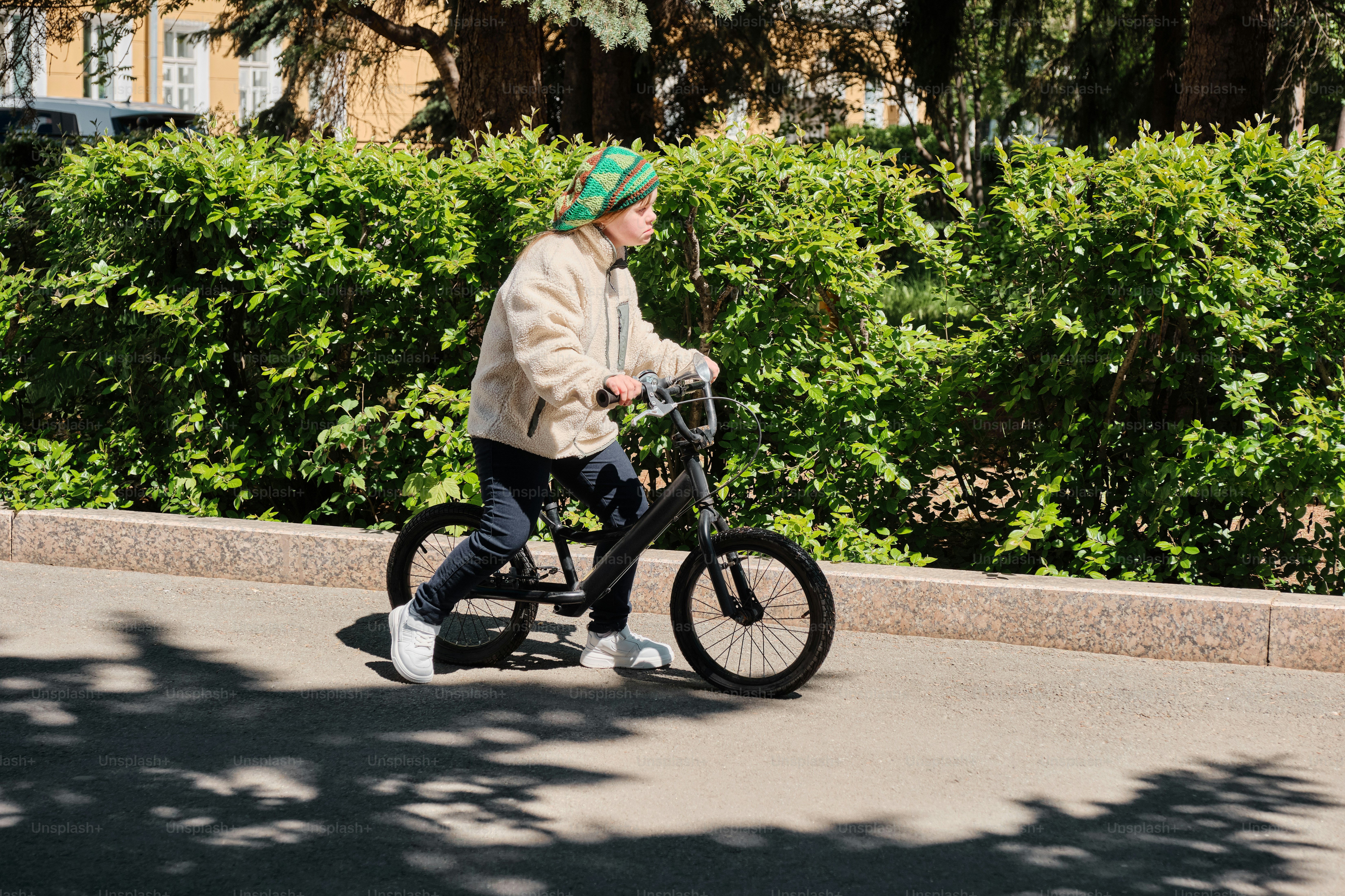 A person riding a bike down a street photo – Special needs child Image ...