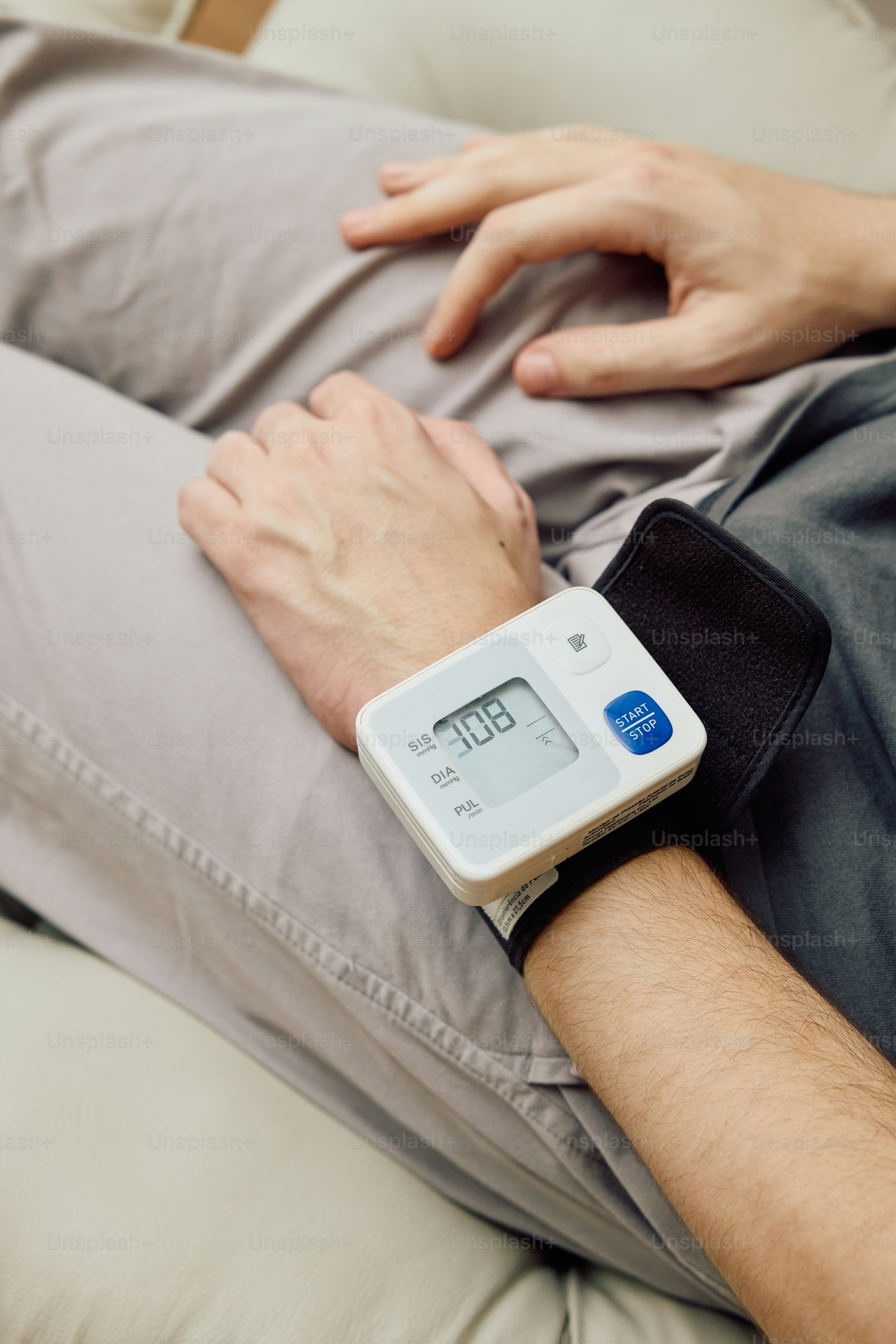 A man laying on a couch with a blood pressure monitor on his arm photo ...
