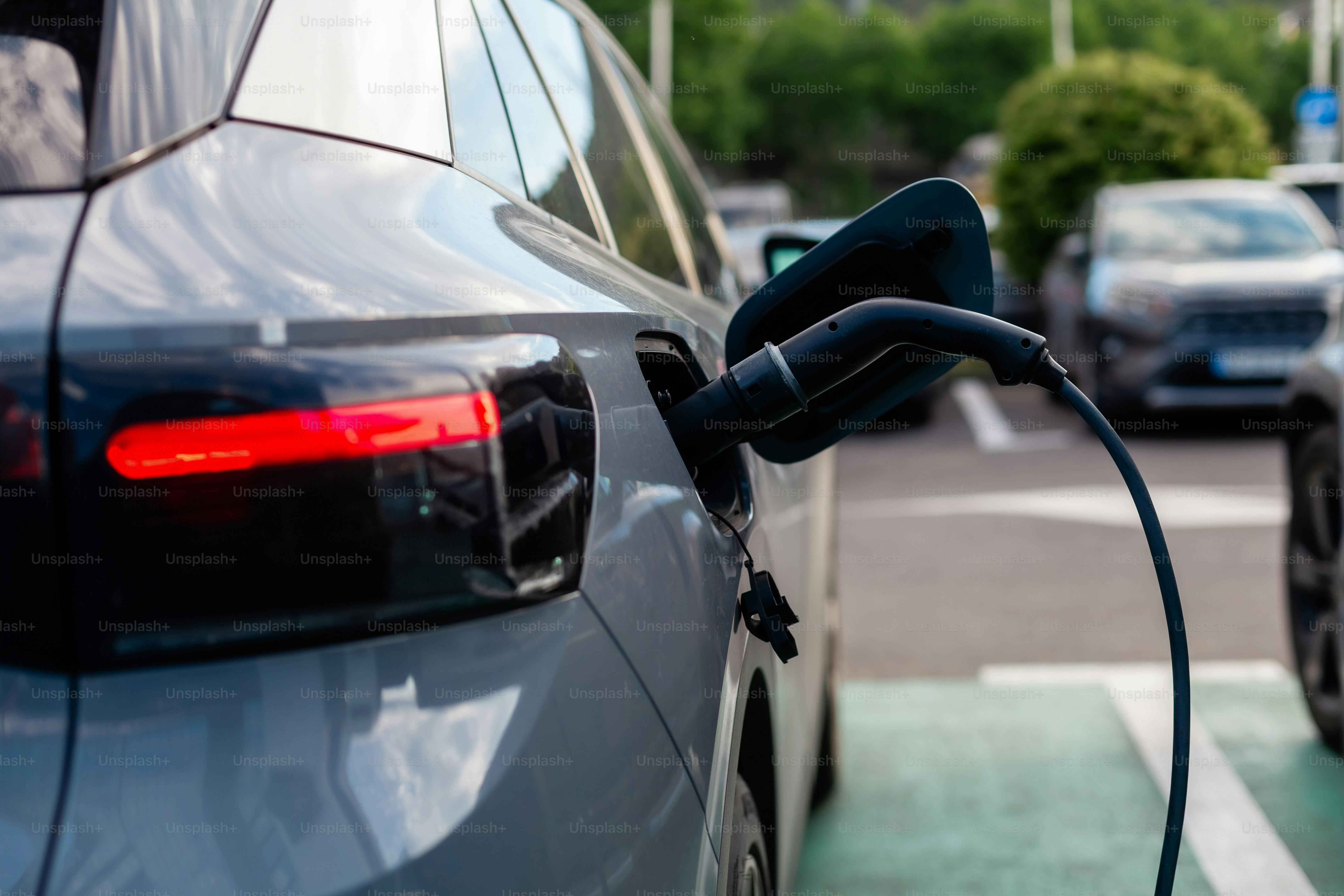 An electric car being charged at a charging station photo ...
