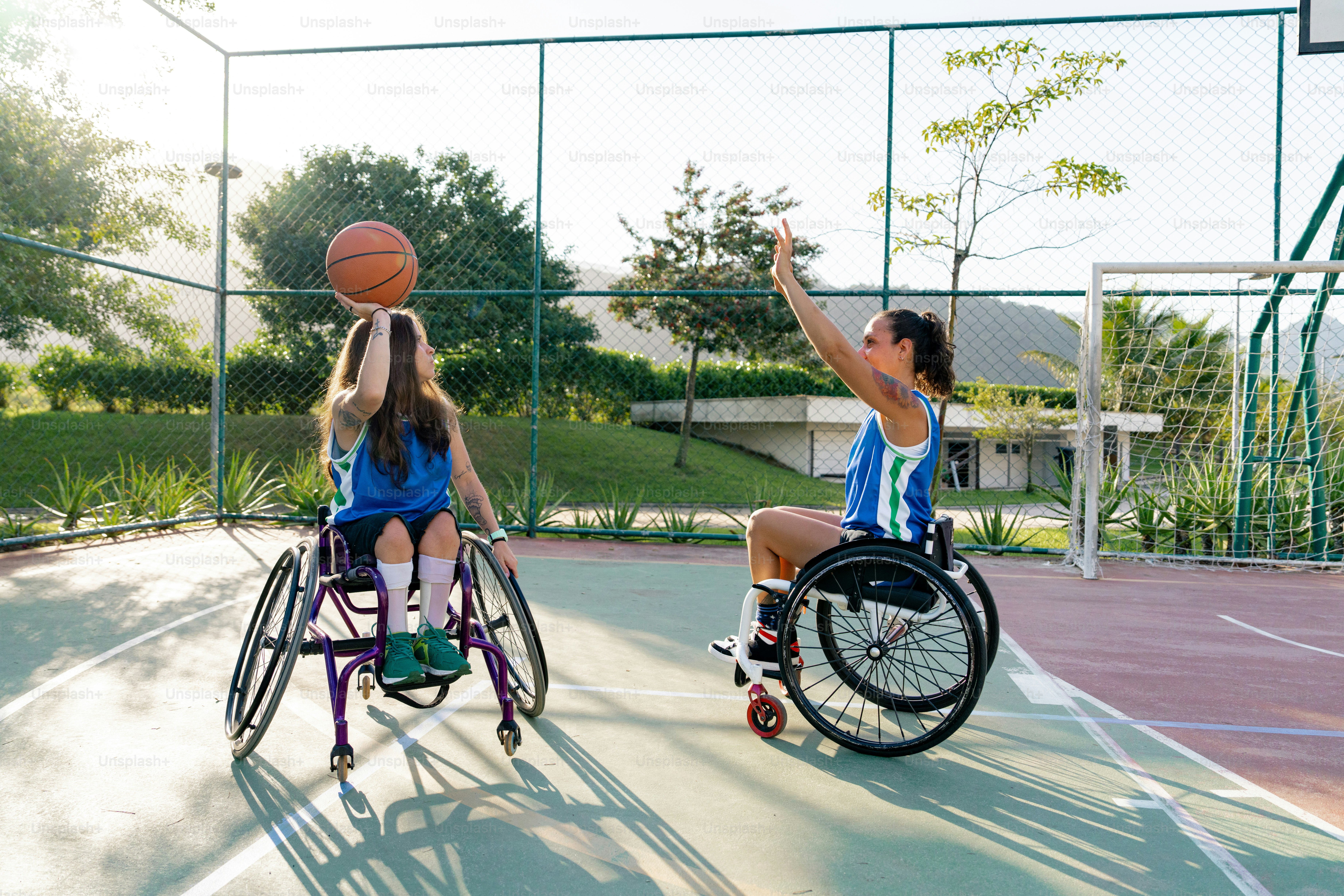 Dos mujeres en silla de ruedas jugando al baloncesto en una cancha foto ...