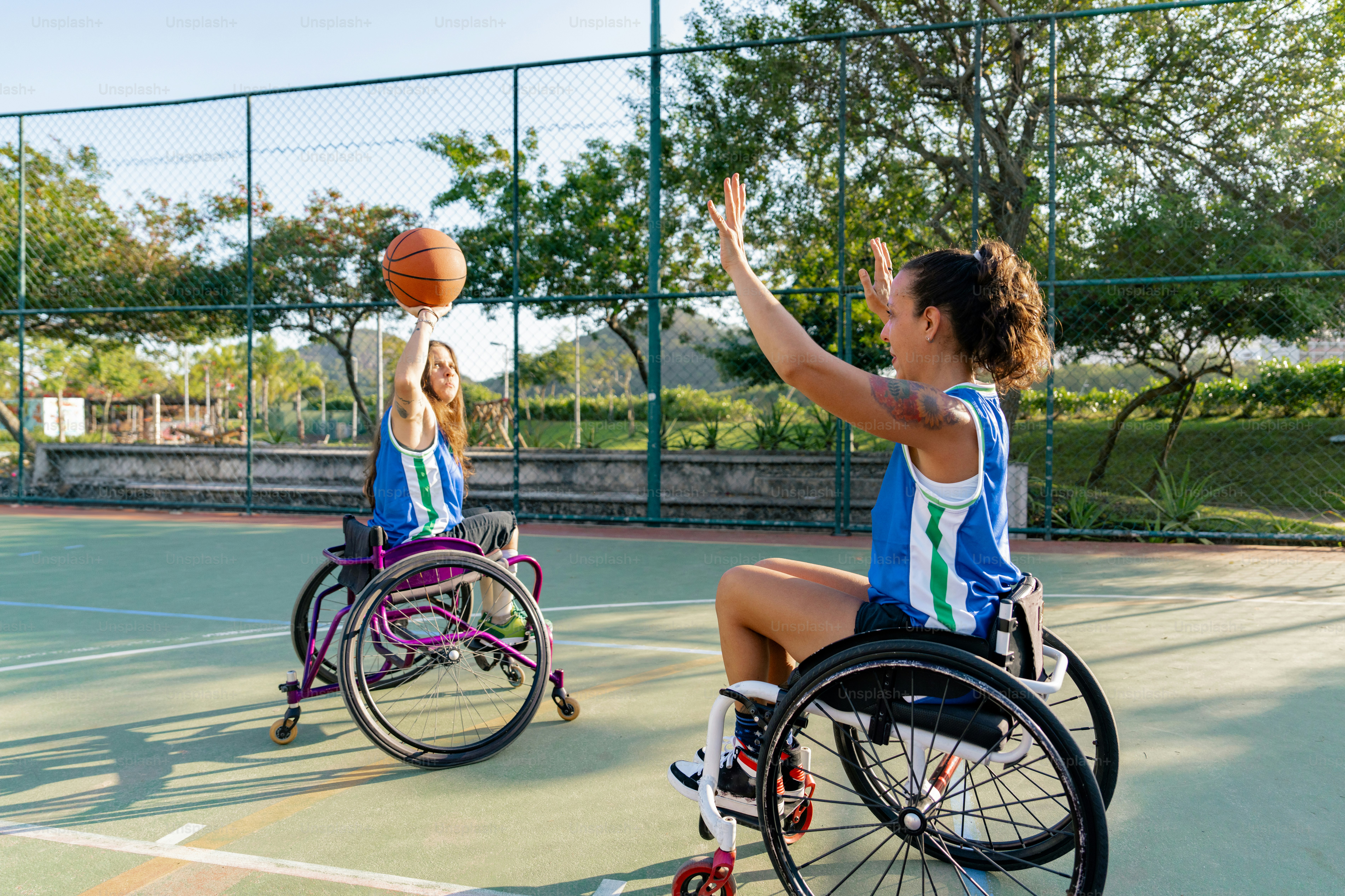Two women in wheelchairs playing basketball on a court photo – Olympic ...