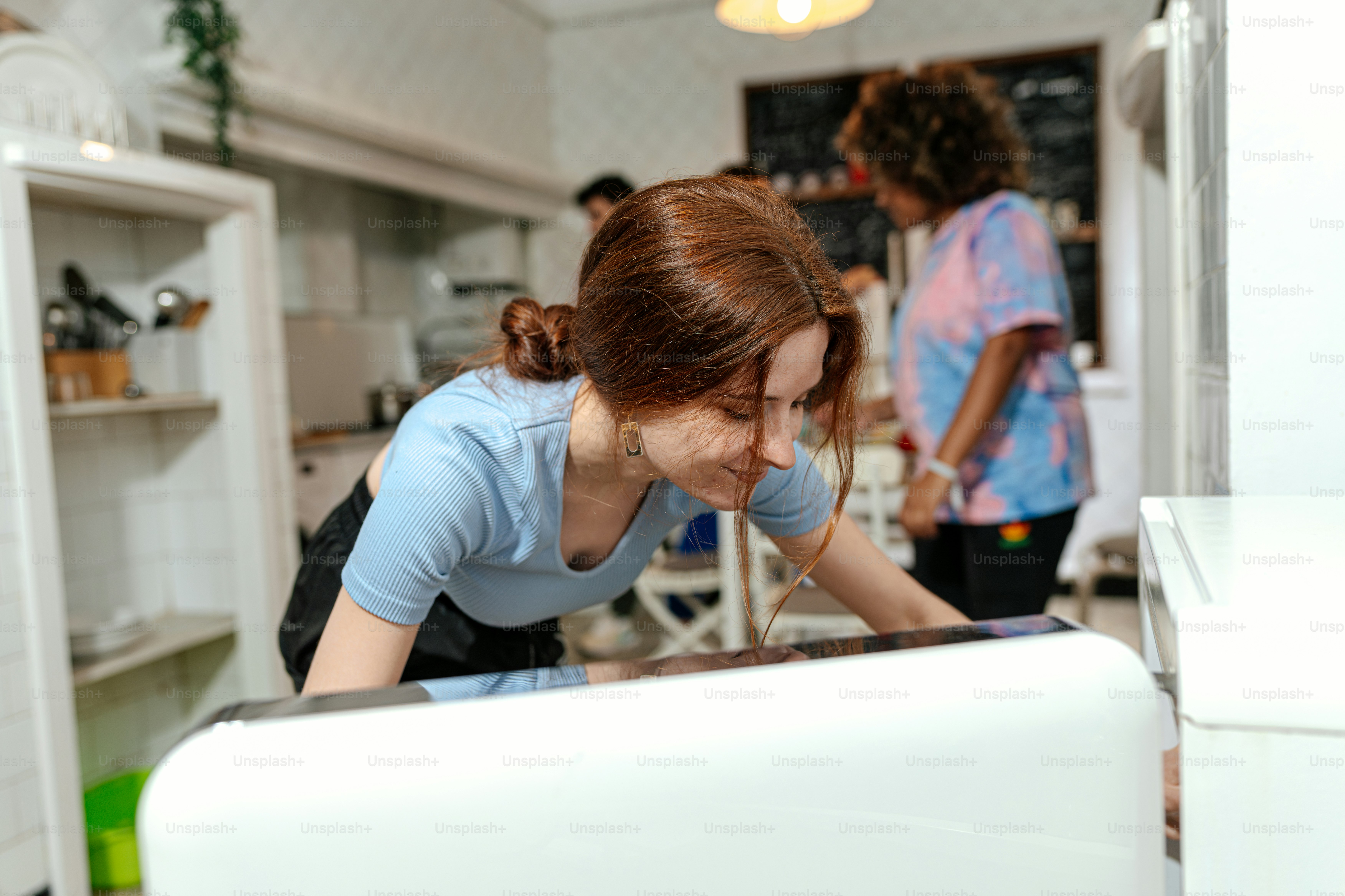 A woman leaning over a refrigerator in a kitchen photo – Kitchen Image ...