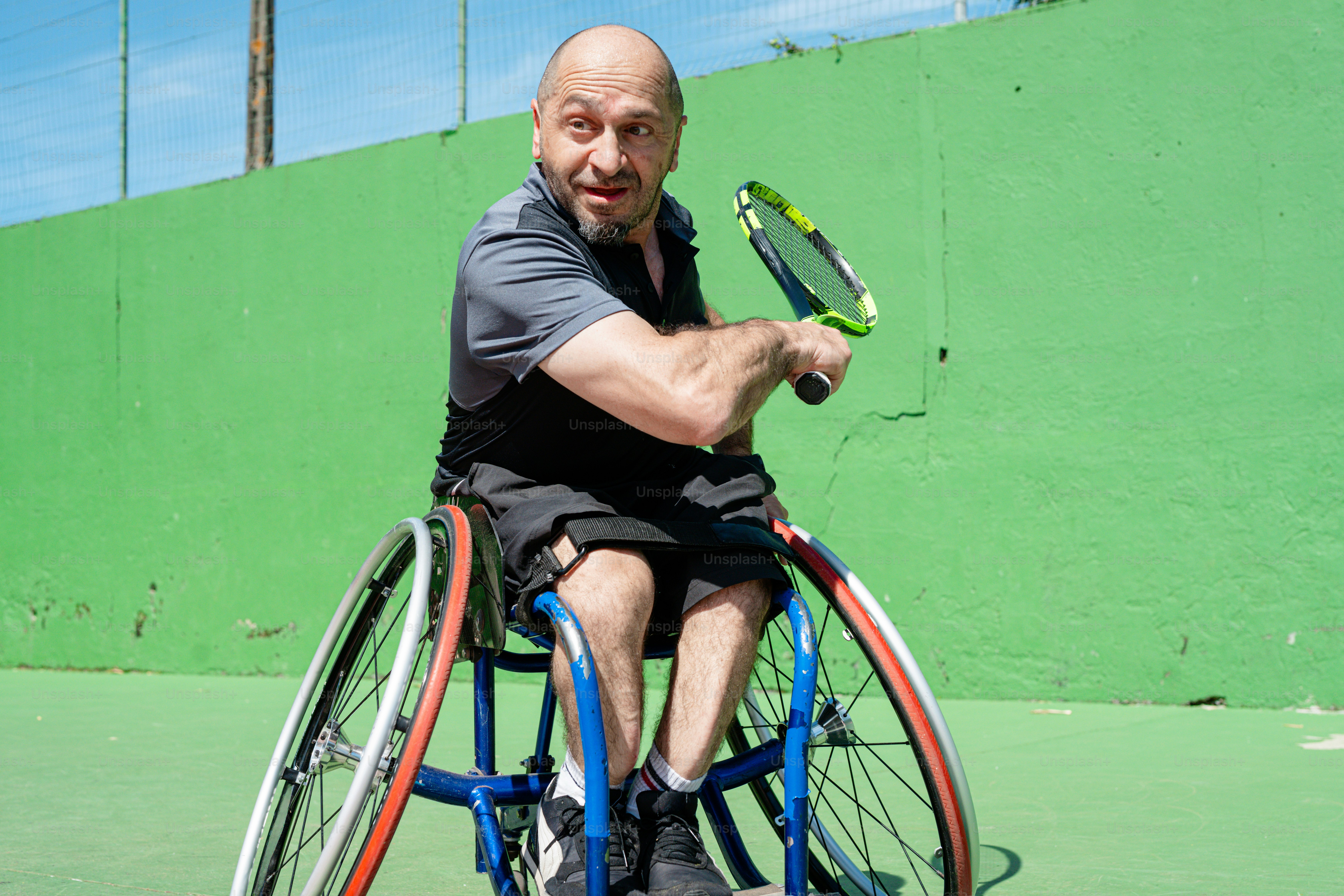 A man in a wheelchair holding a tennis racket photo – Disability Image ...