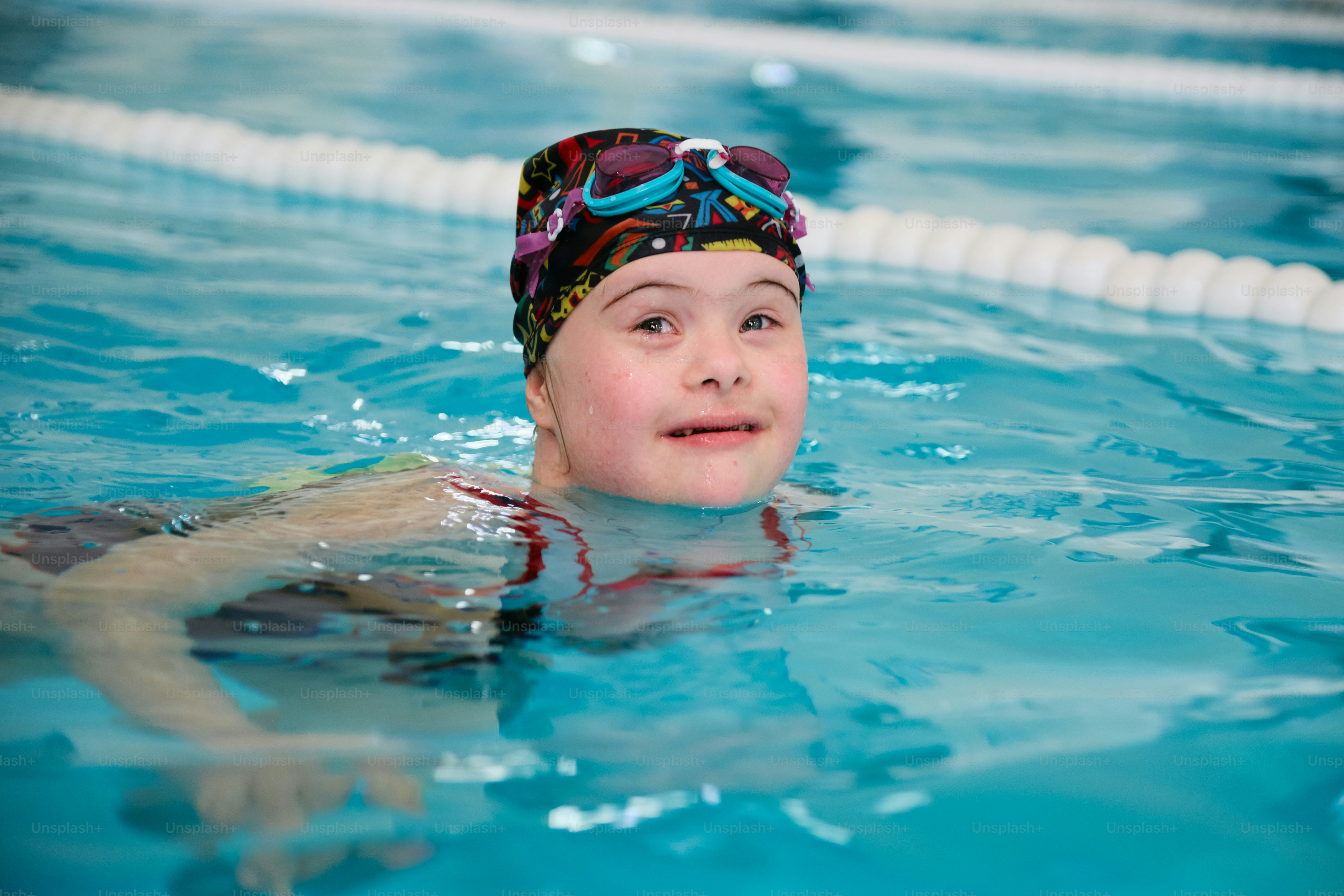 A young girl swimming in a pool wearing a swimming cap photo – Swimming ...