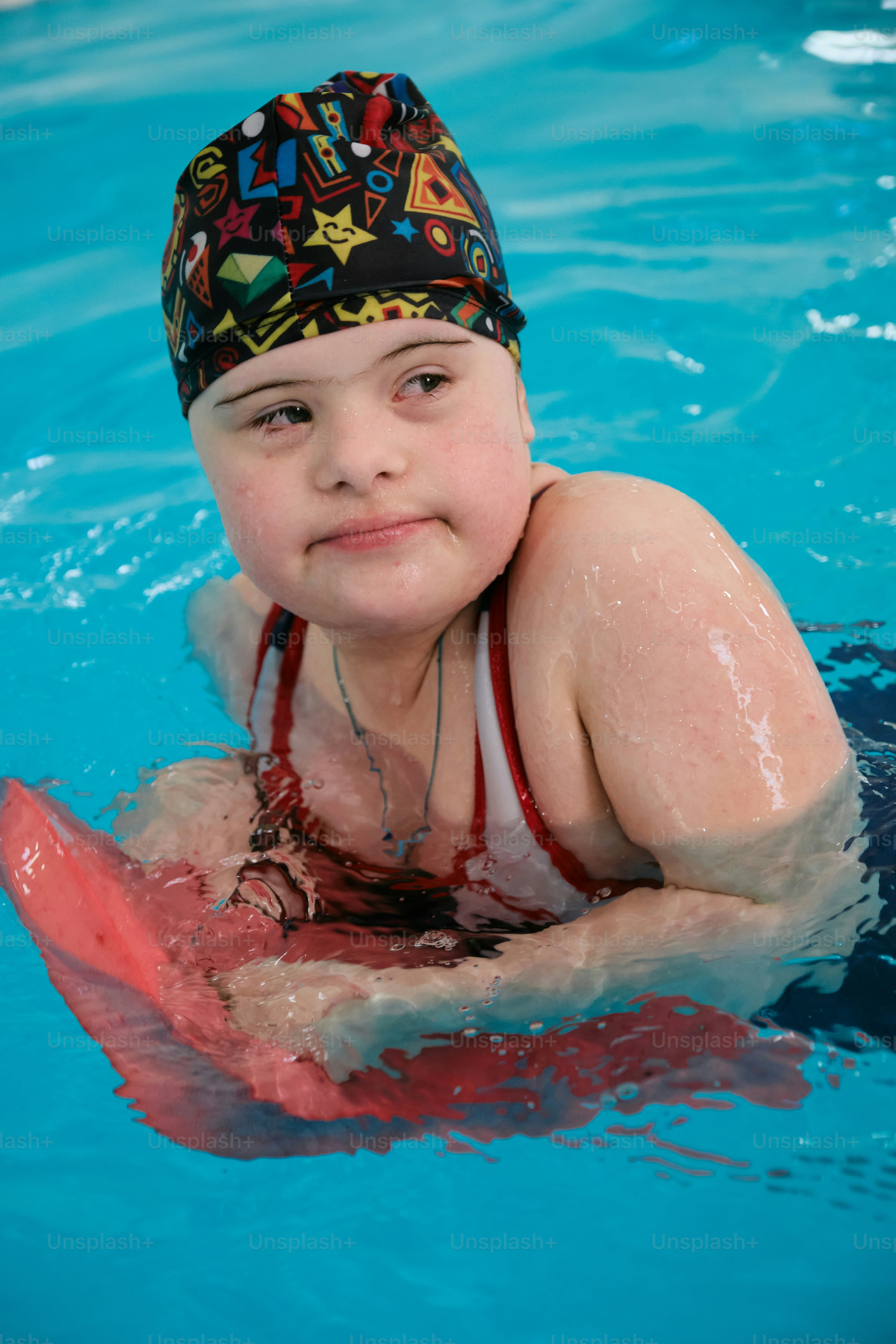 A young boy swimming in a pool wearing a swim cap photo – Disability ...