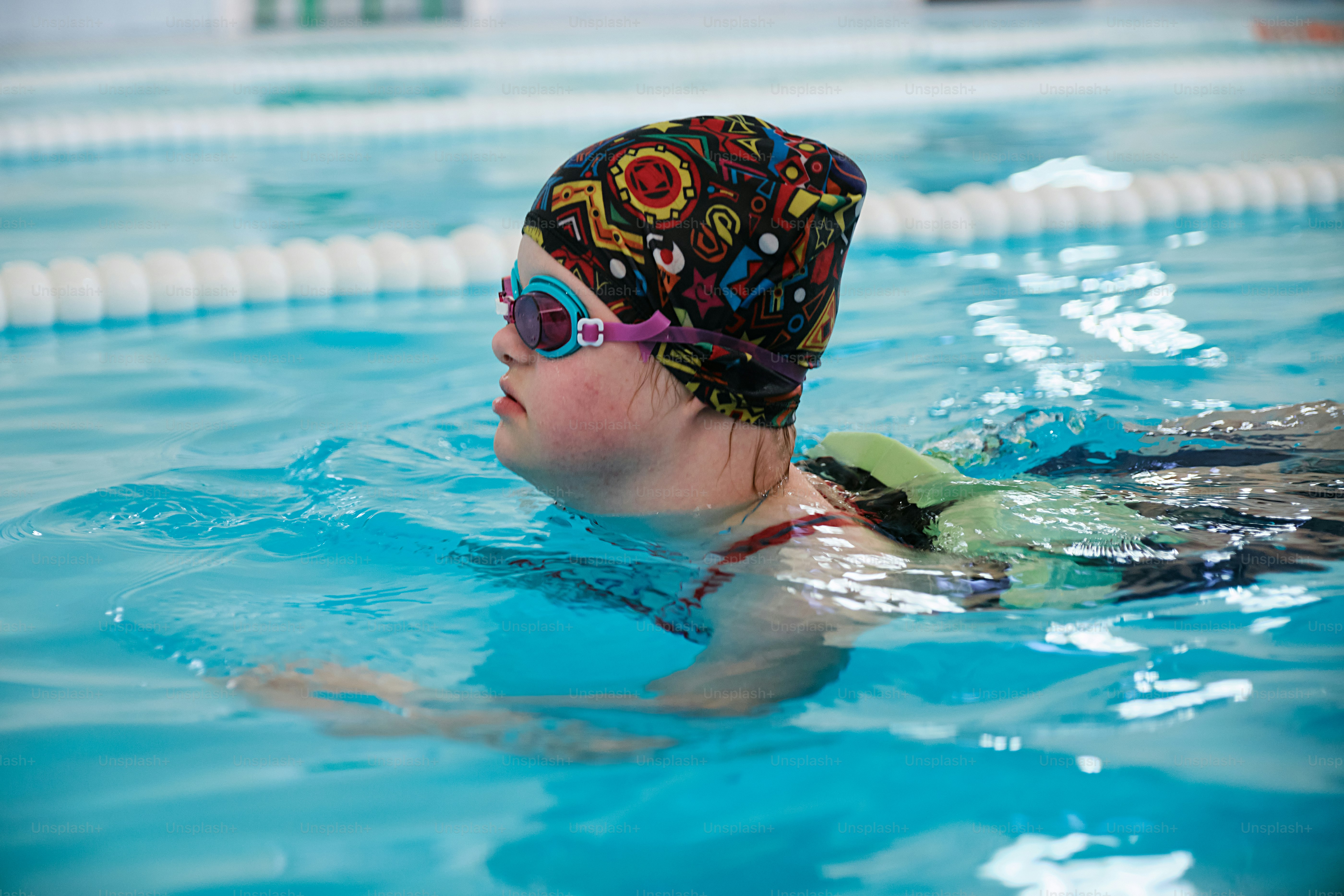 A young girl swimming in a pool wearing a swimming cap photo – Swimming ...