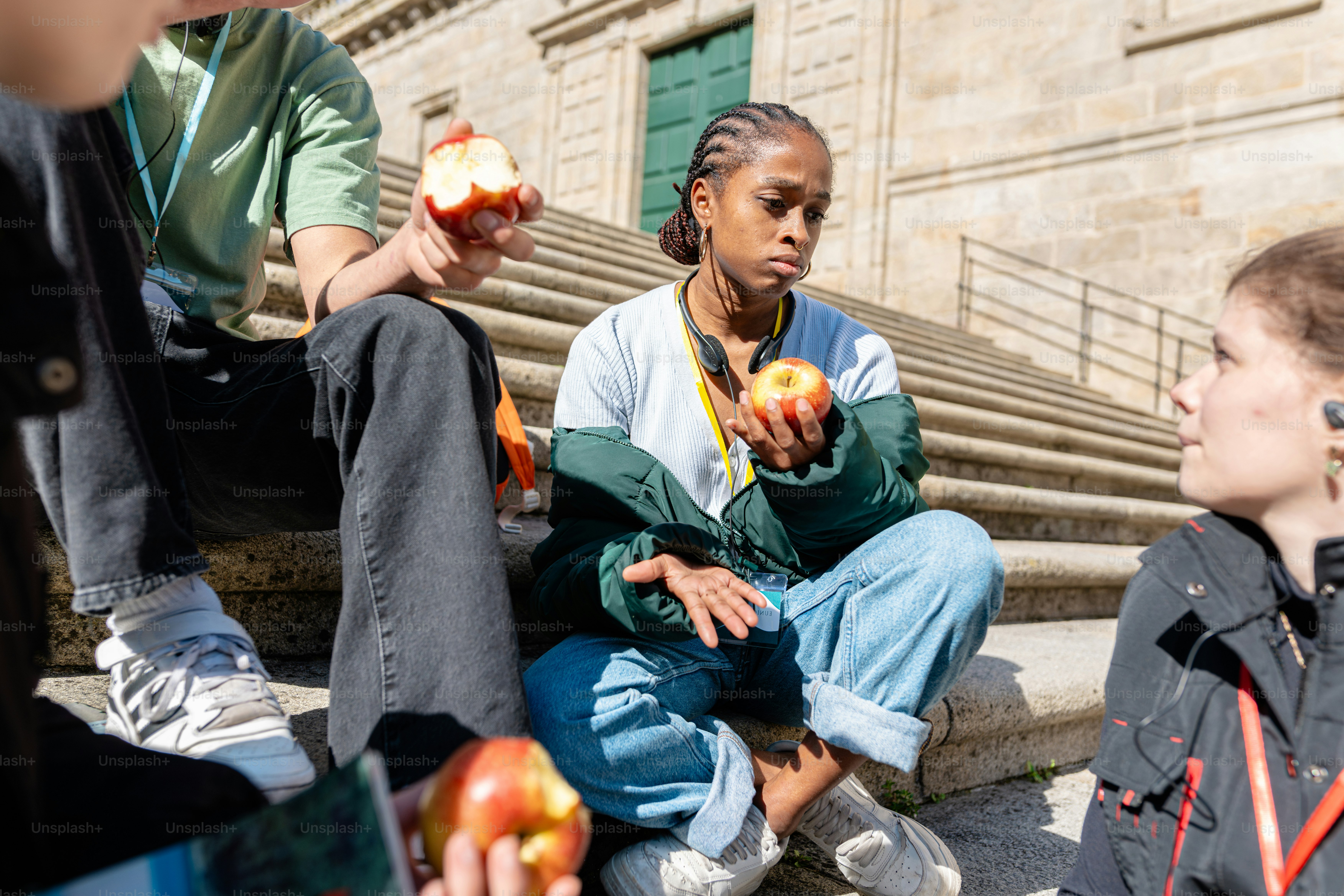 A group of people sitting on steps eating apples photo – Travel Image ...