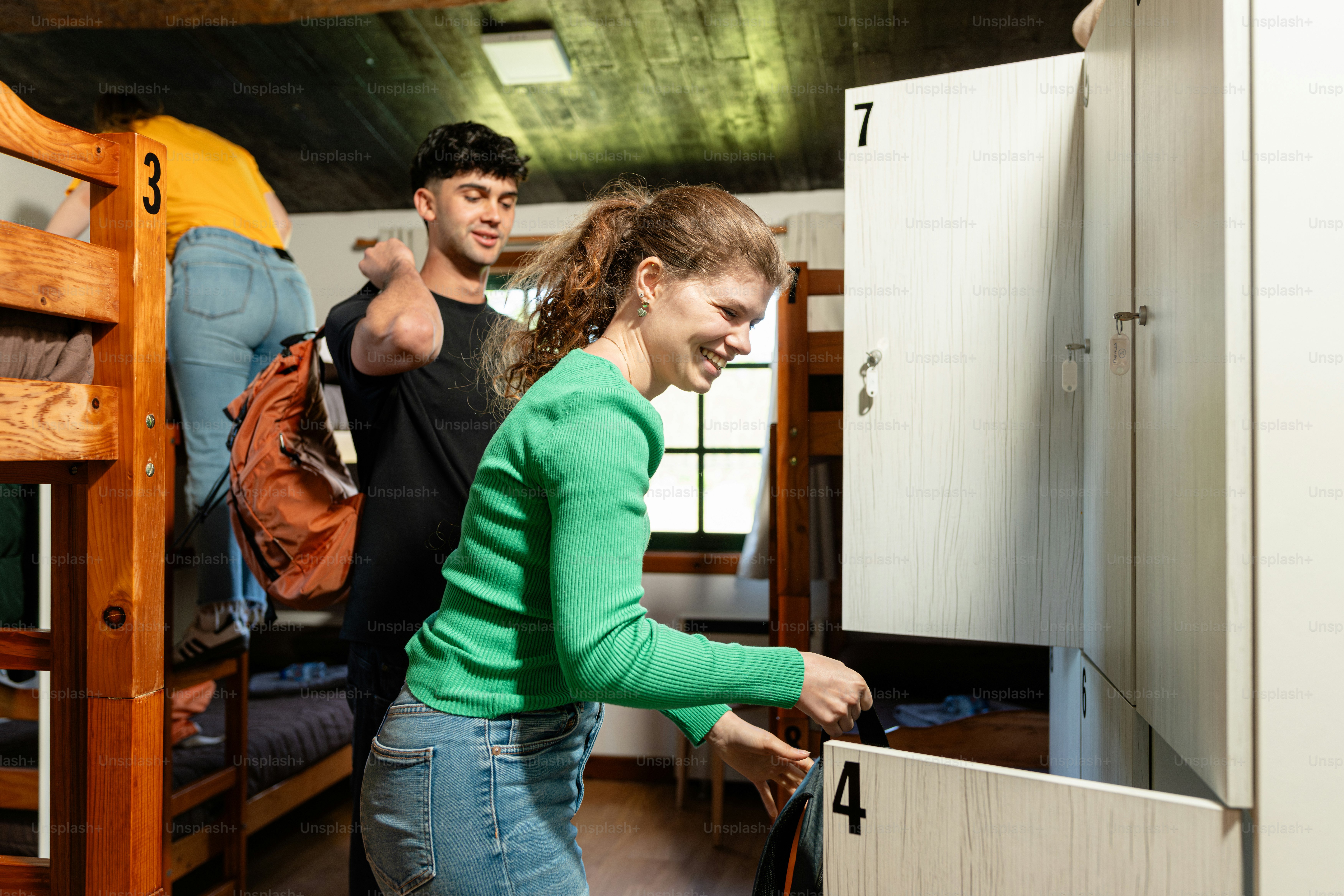 A man and a woman standing in a room with bunk beds photo – Hostel ...
