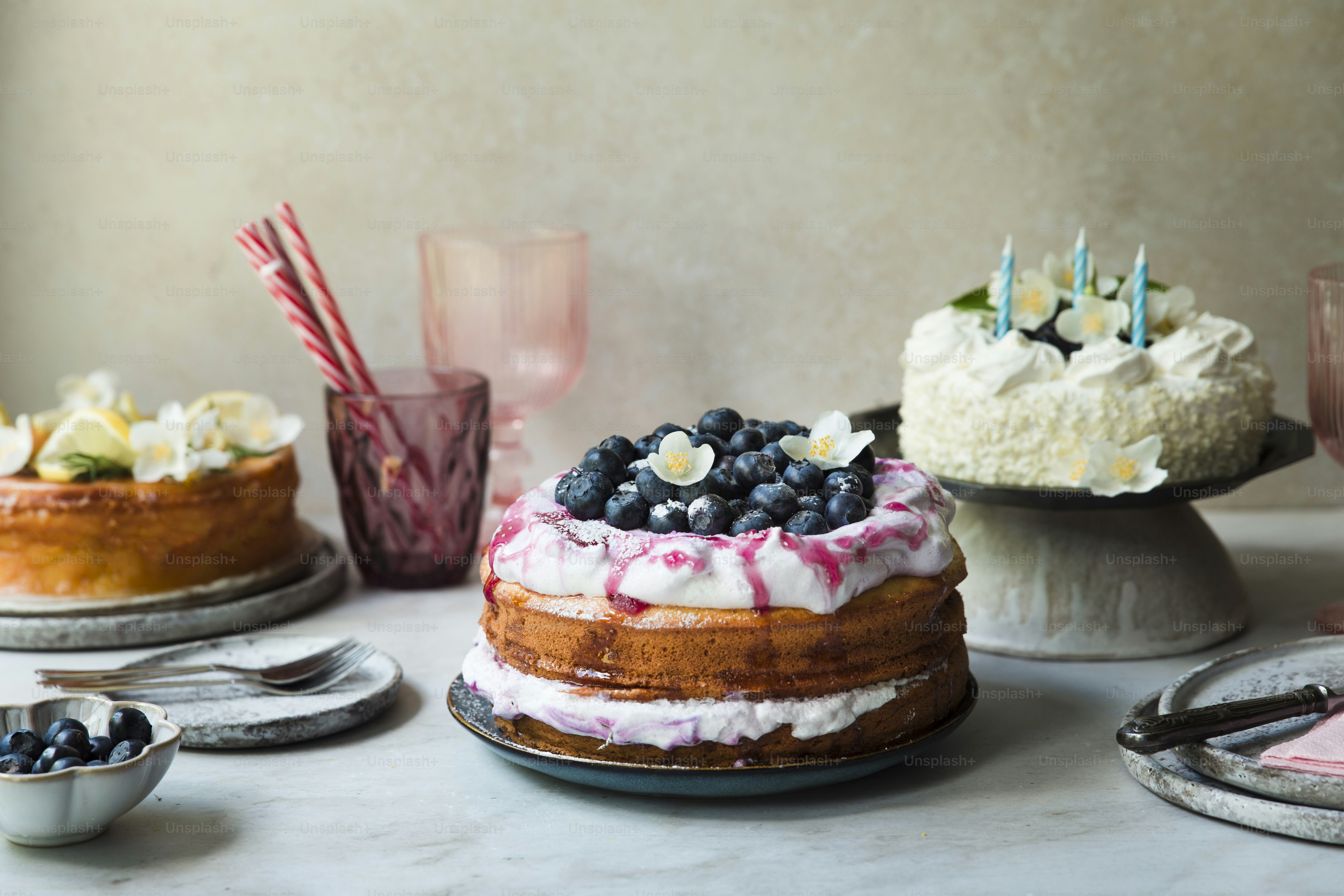 A table topped with cakes covered in frosting and blueberries photo ...