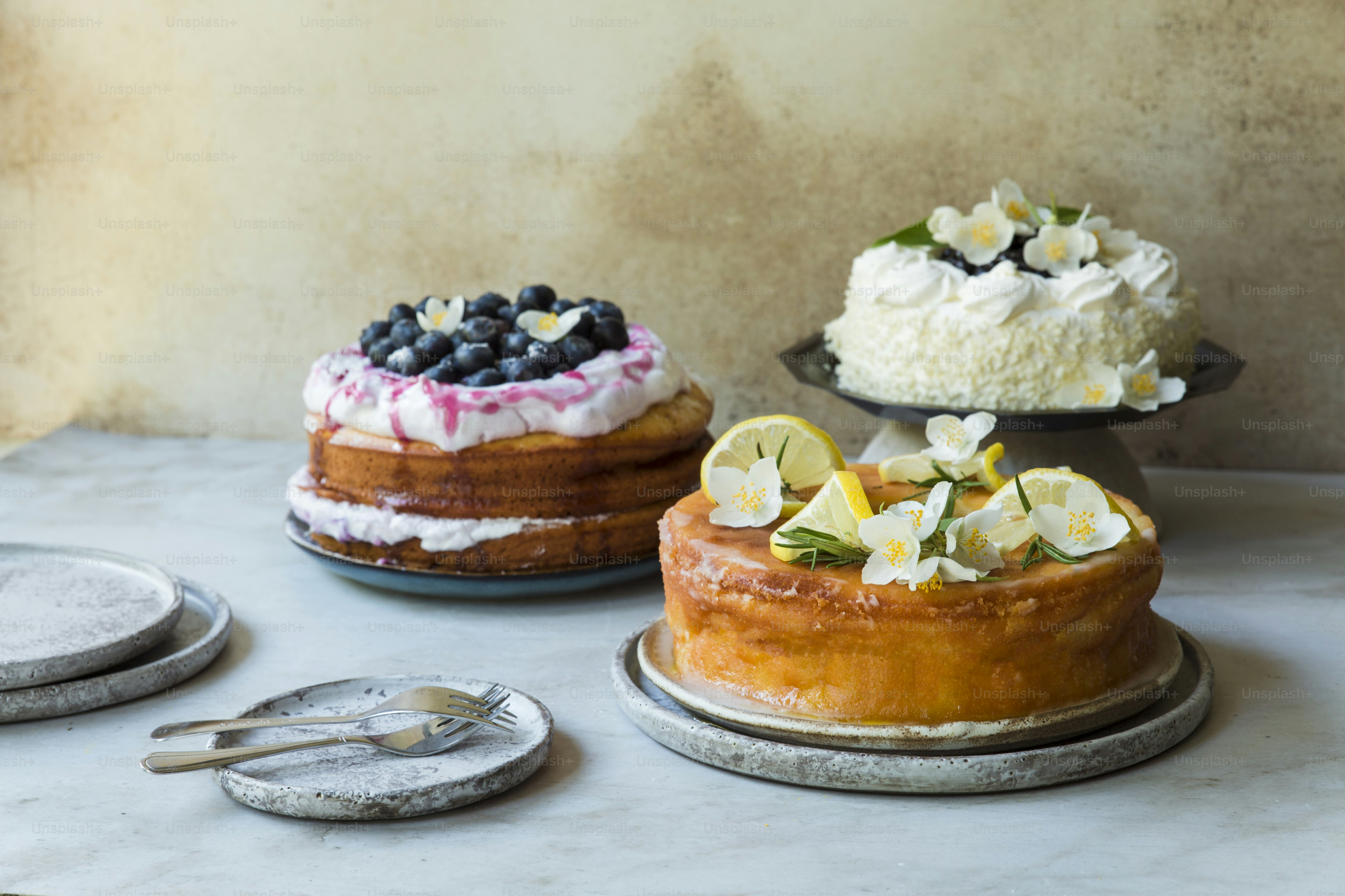 A table topped with two cakes covered in frosting photo – Cakes Image ...