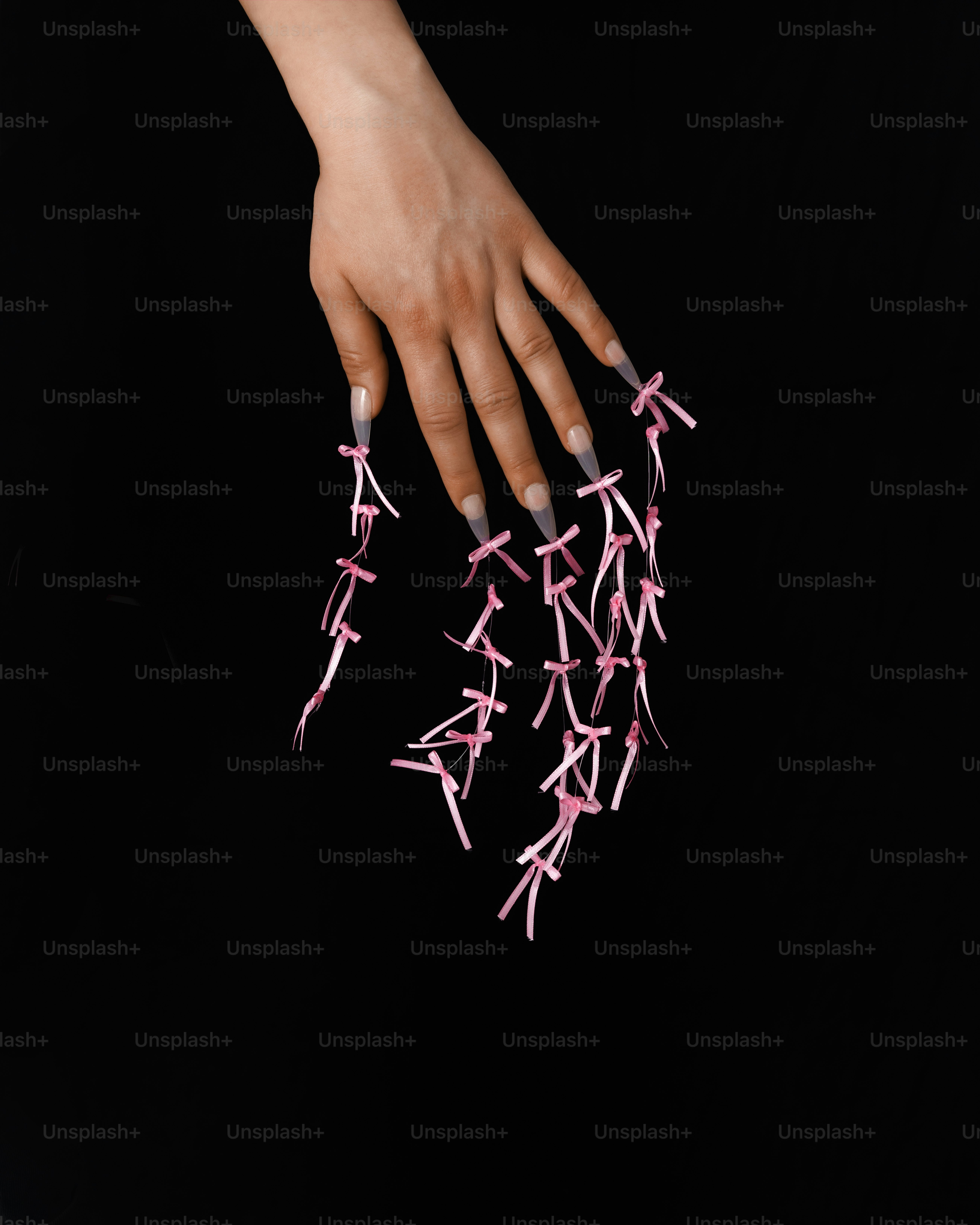 A woman's hand holding a string of pink sticks photo – Long nails Image ...