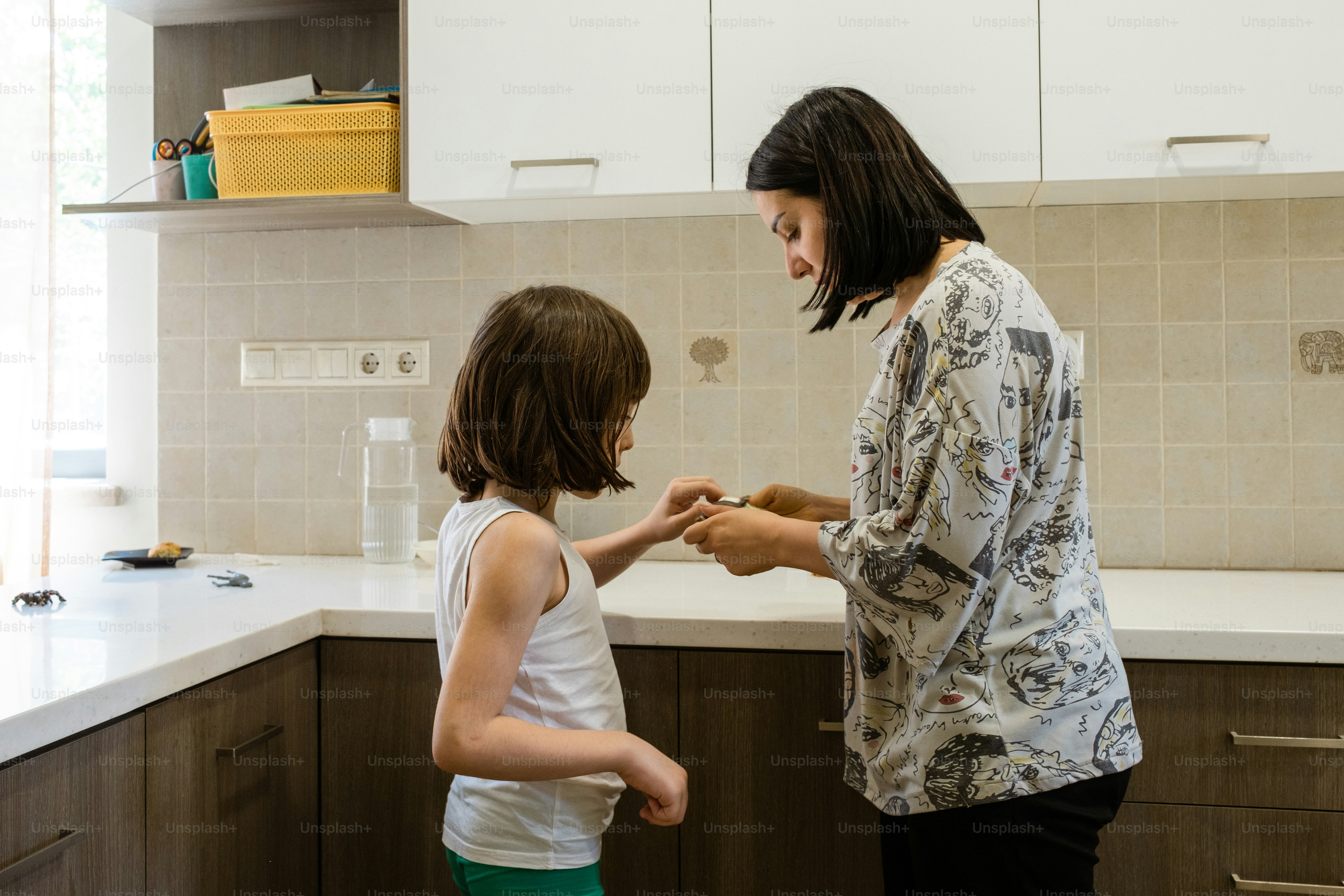 A woman helping a little girl put something in her hand photo ...