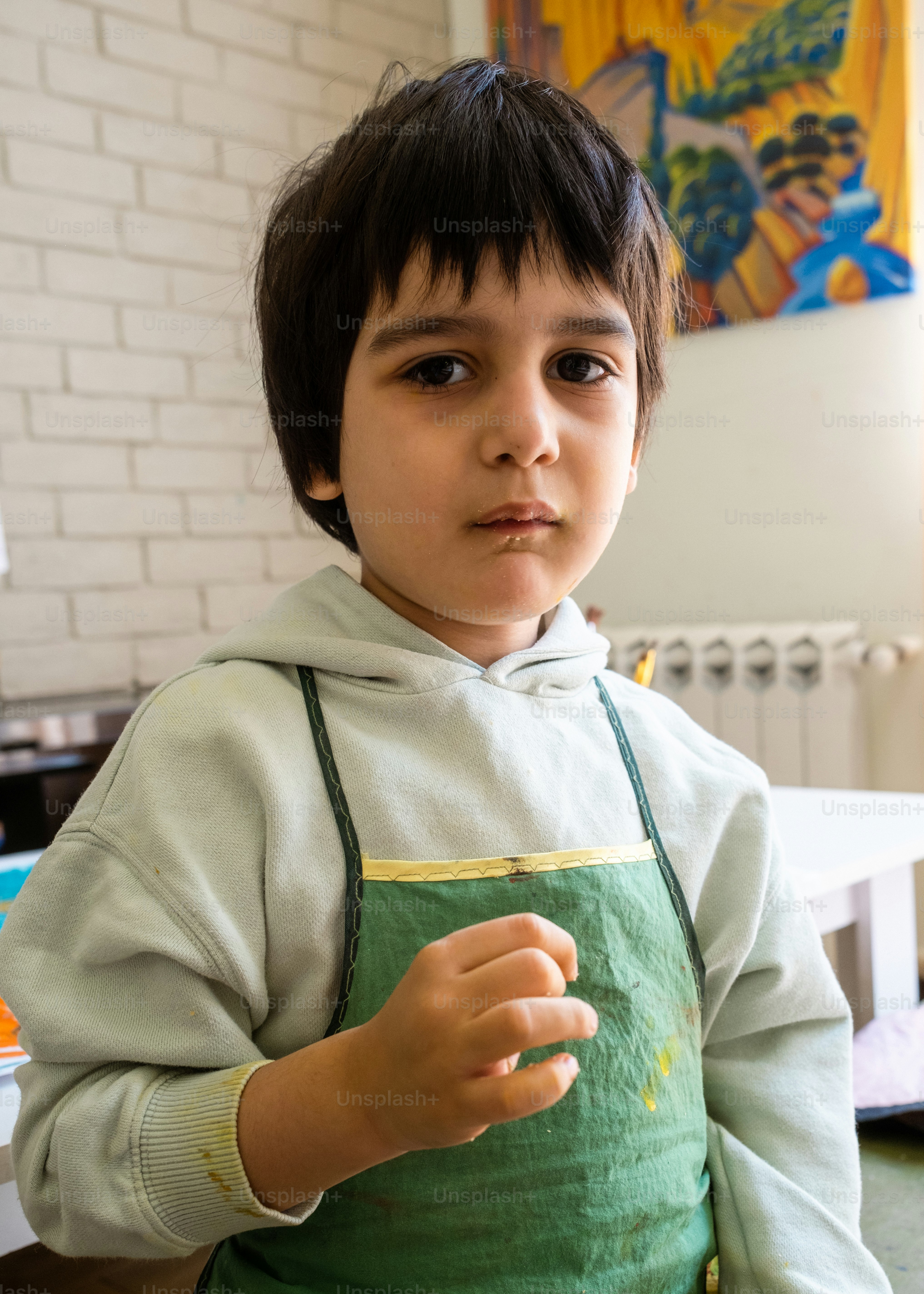 A young boy wearing a green apron holding a fork photo – Autism Image ...