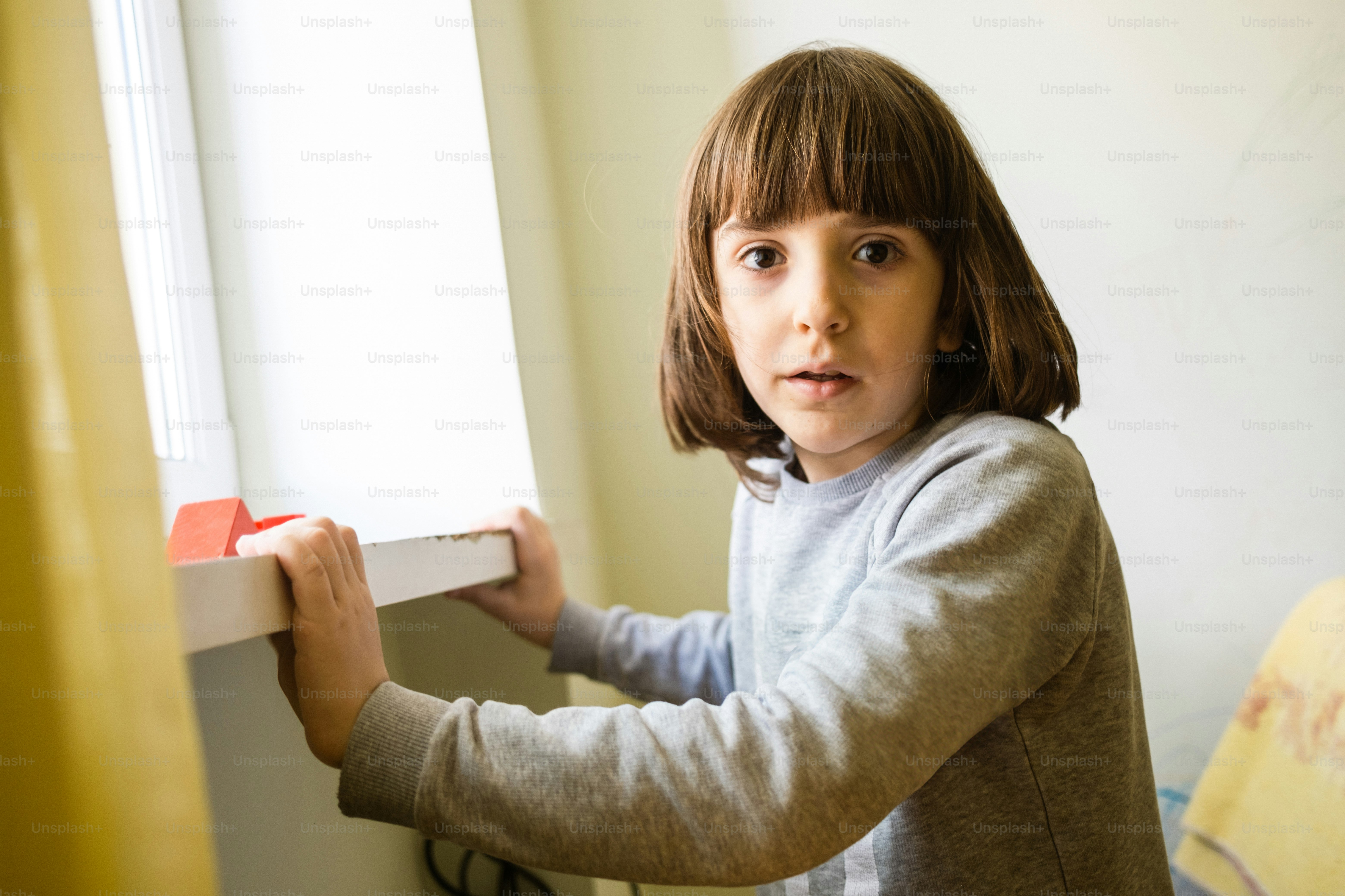 A little girl is holding a window in her hand photo – Childrens health ...