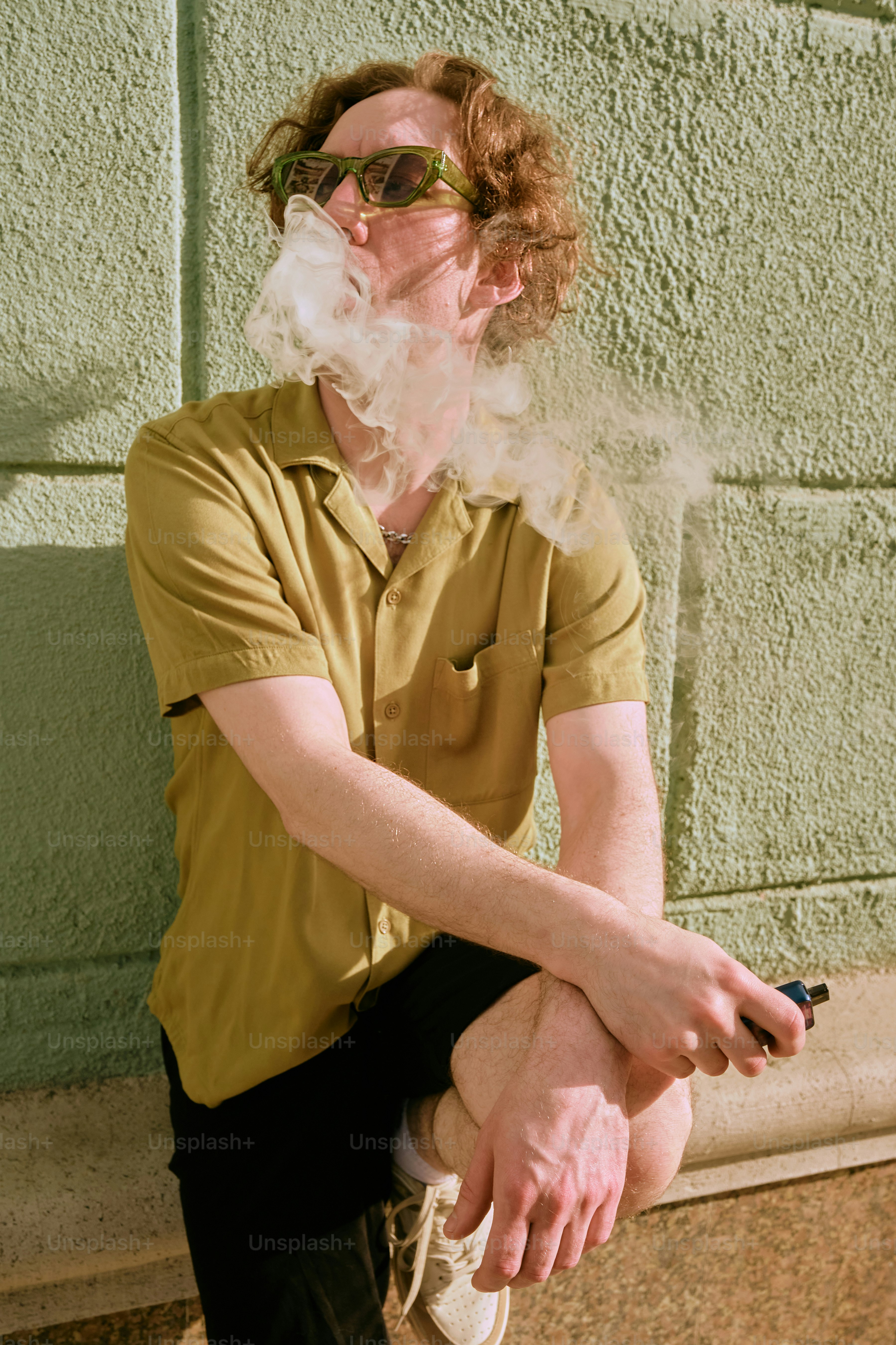 A man sitting on a curb smoking a cigarette photo – Vaping Image on ...