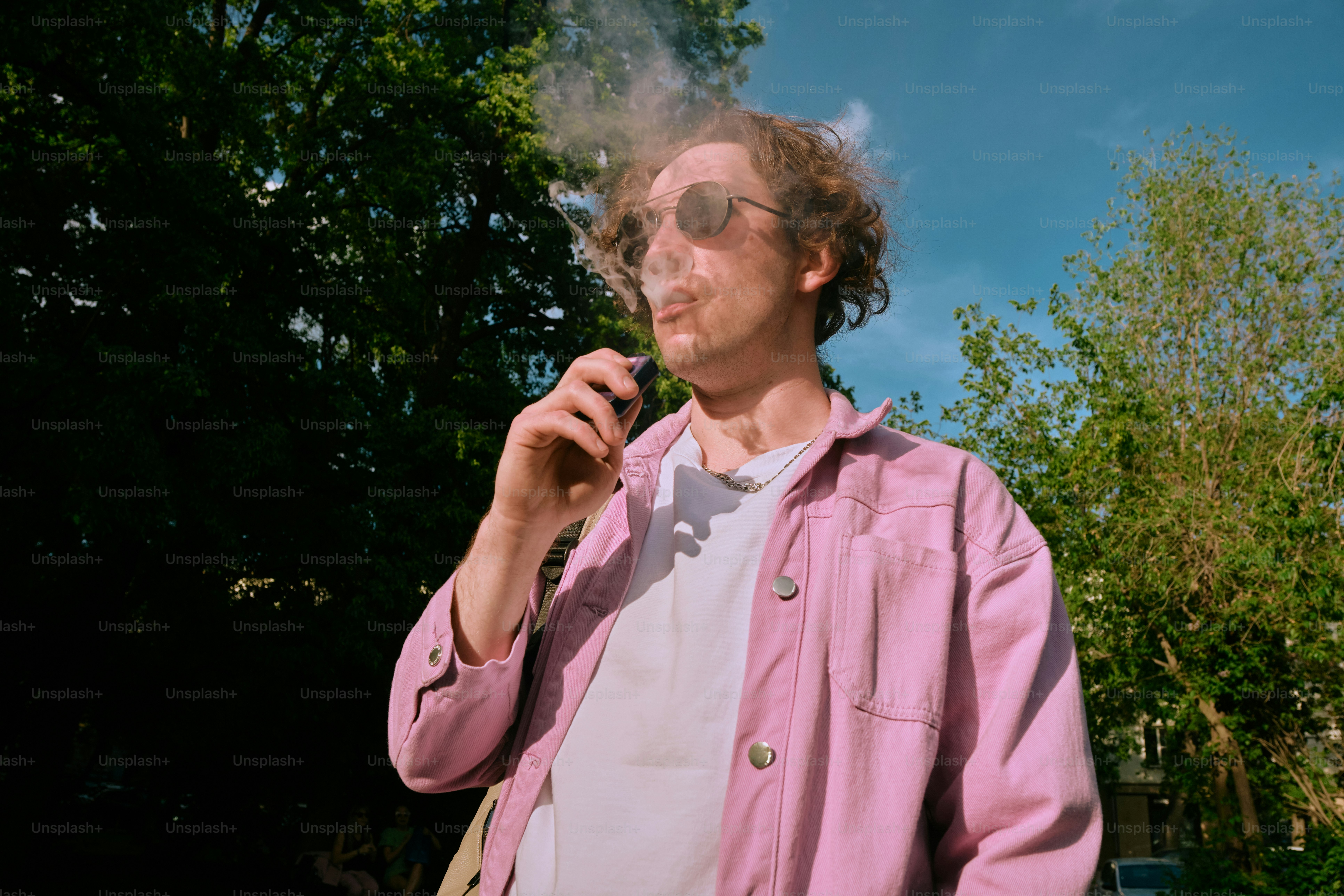 A man in a pink shirt smoking a cigarette photo – Vaping Image on Unsplash