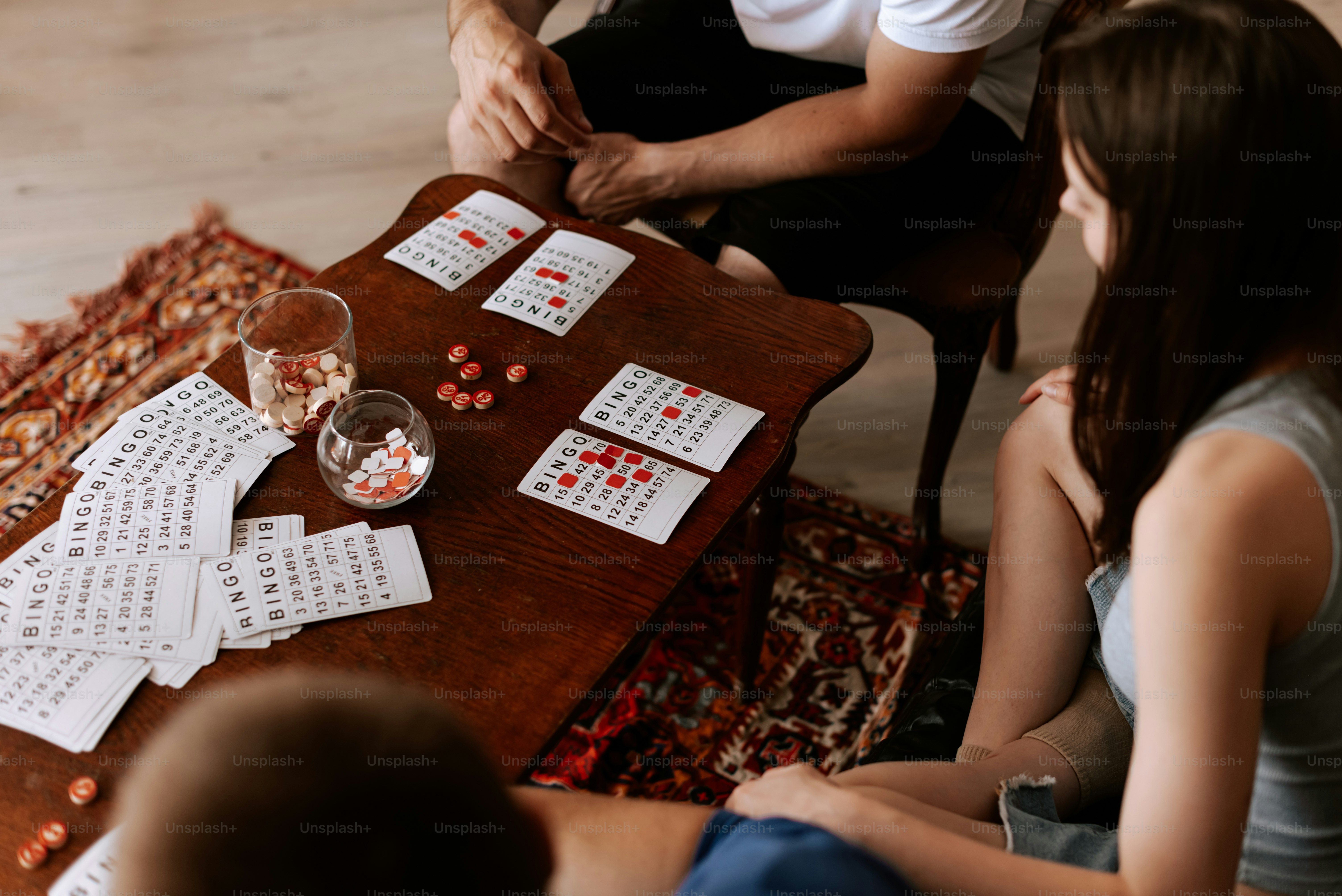 A group of people sitting around a table playing cards photo – Bingo ...