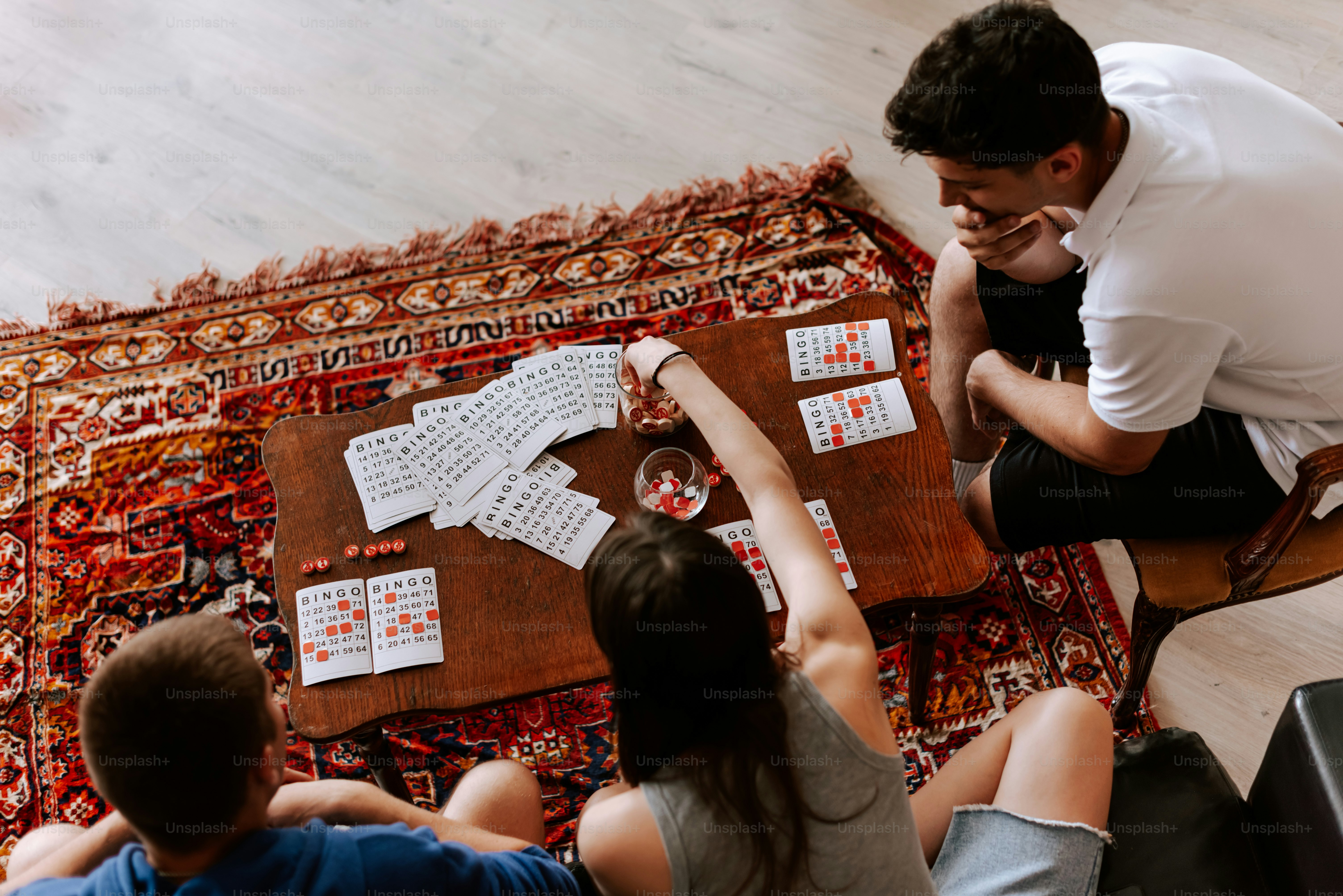 A group of people sitting around a table playing cards photo – Bingo ...