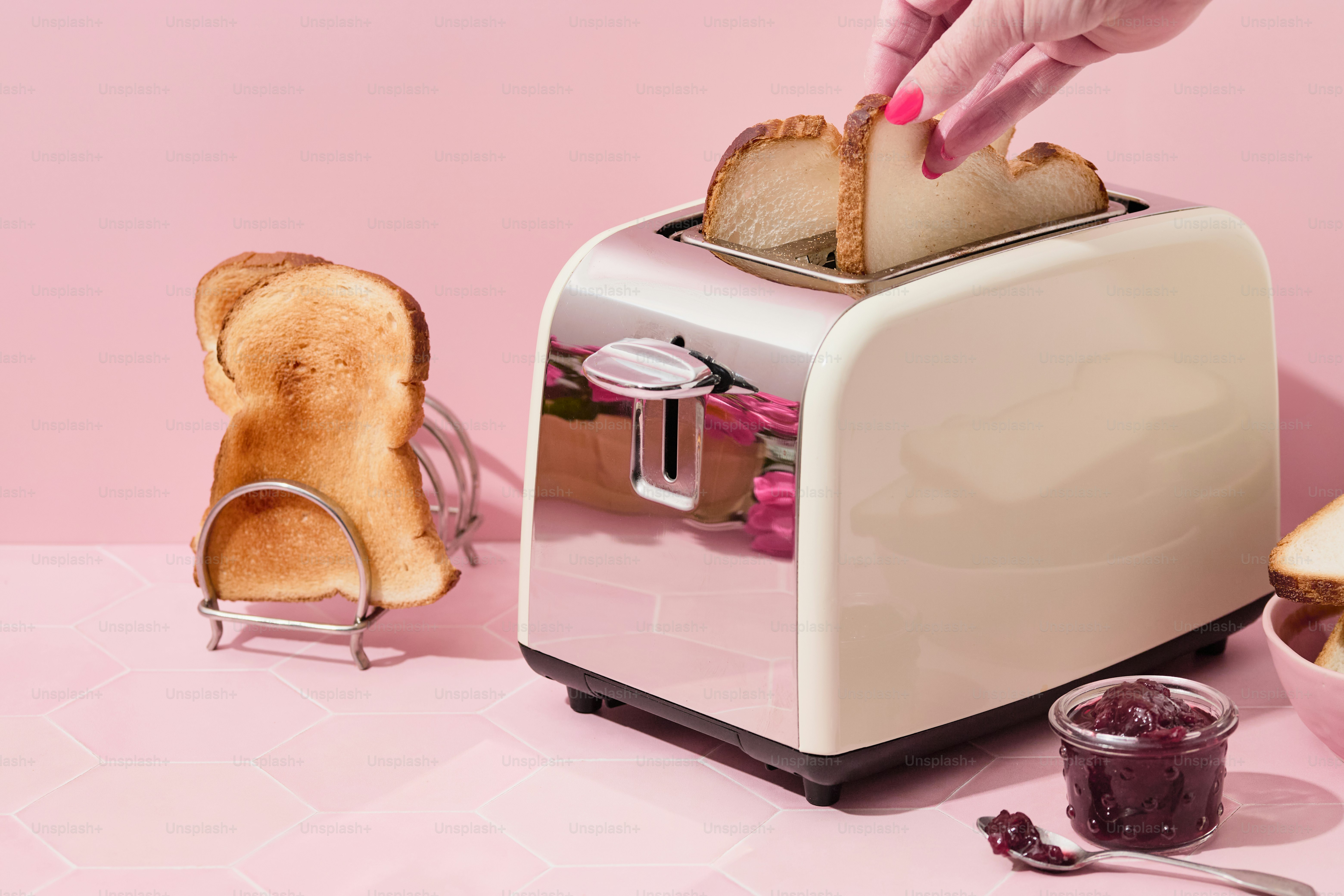 A person putting a slice of bread into a toaster photo – Breakfast ...