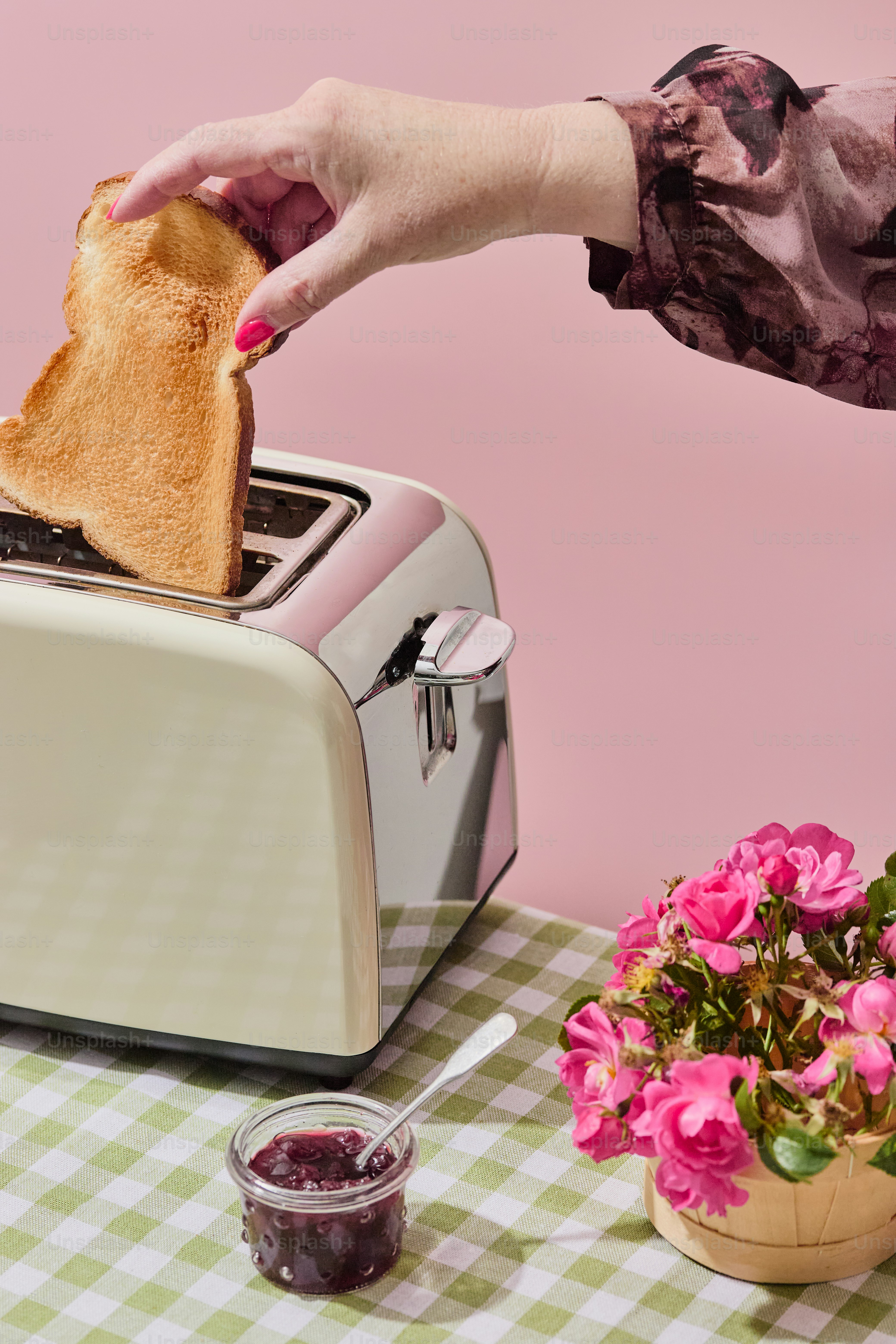 A woman is putting a slice of toast into a toaster photo – Cooking with ...