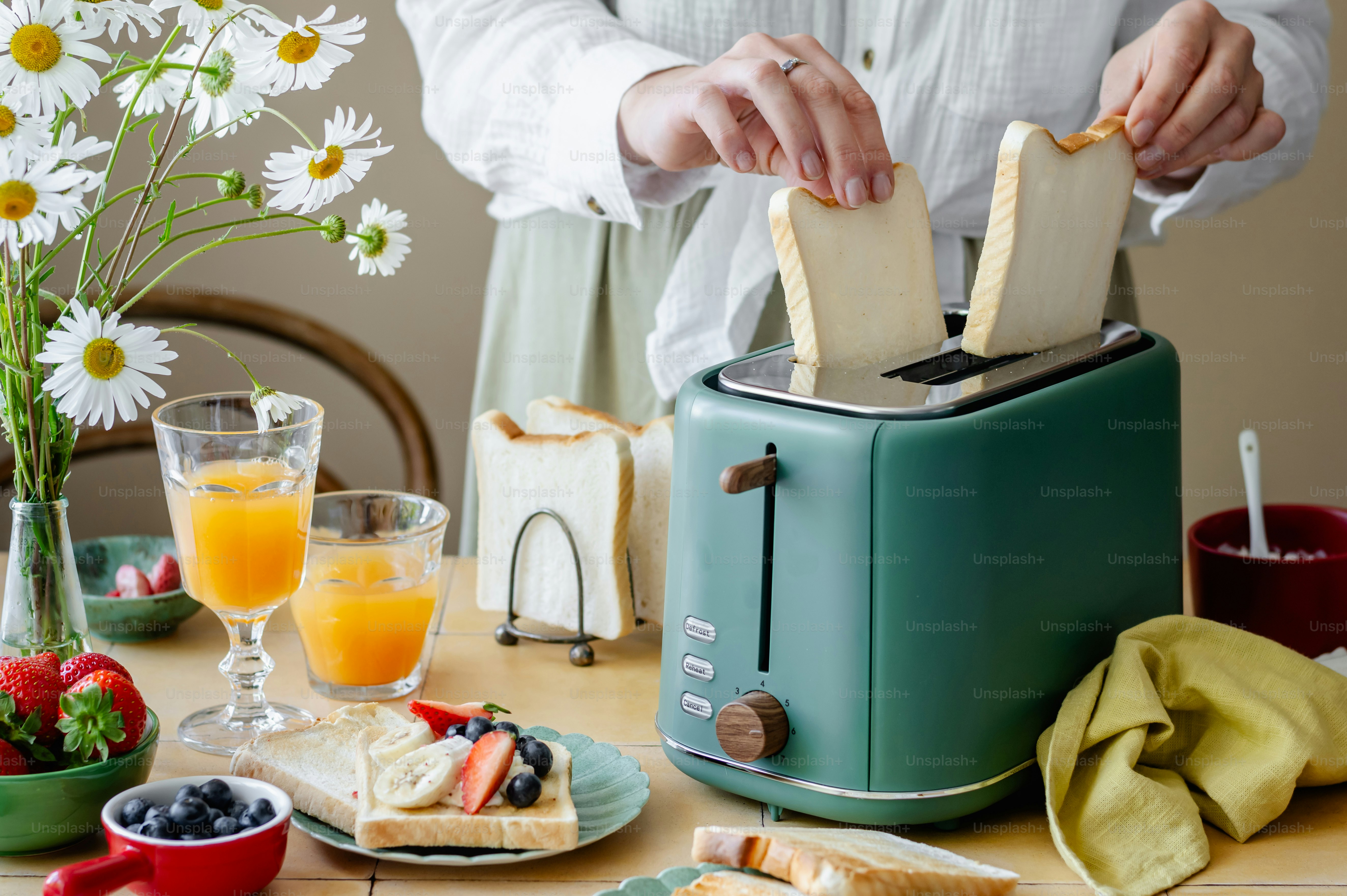 A woman is putting toast into a toaster photo – Technology Image on ...