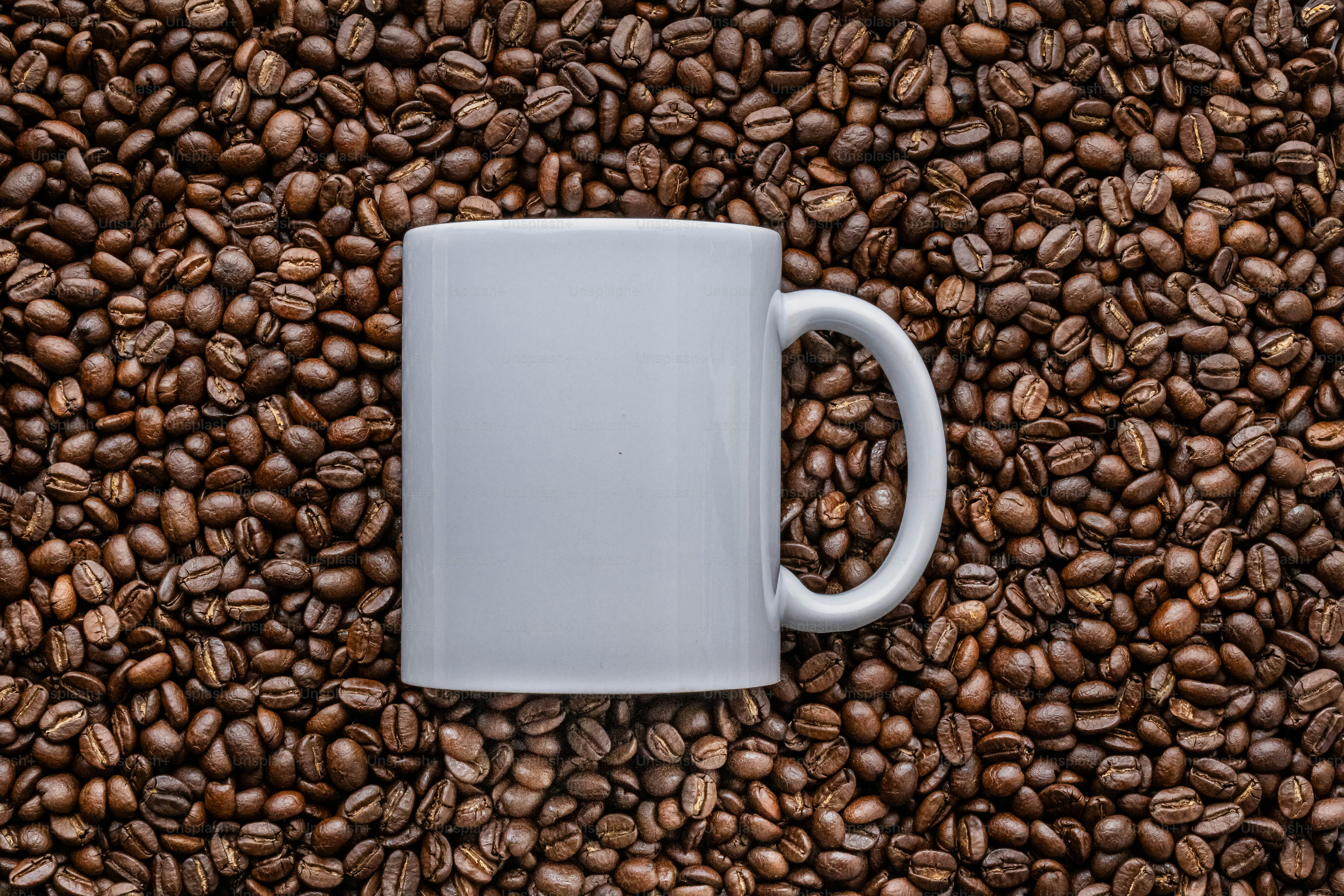 A white coffee cup sitting on top of a pile of coffee beans photo – Mug ...