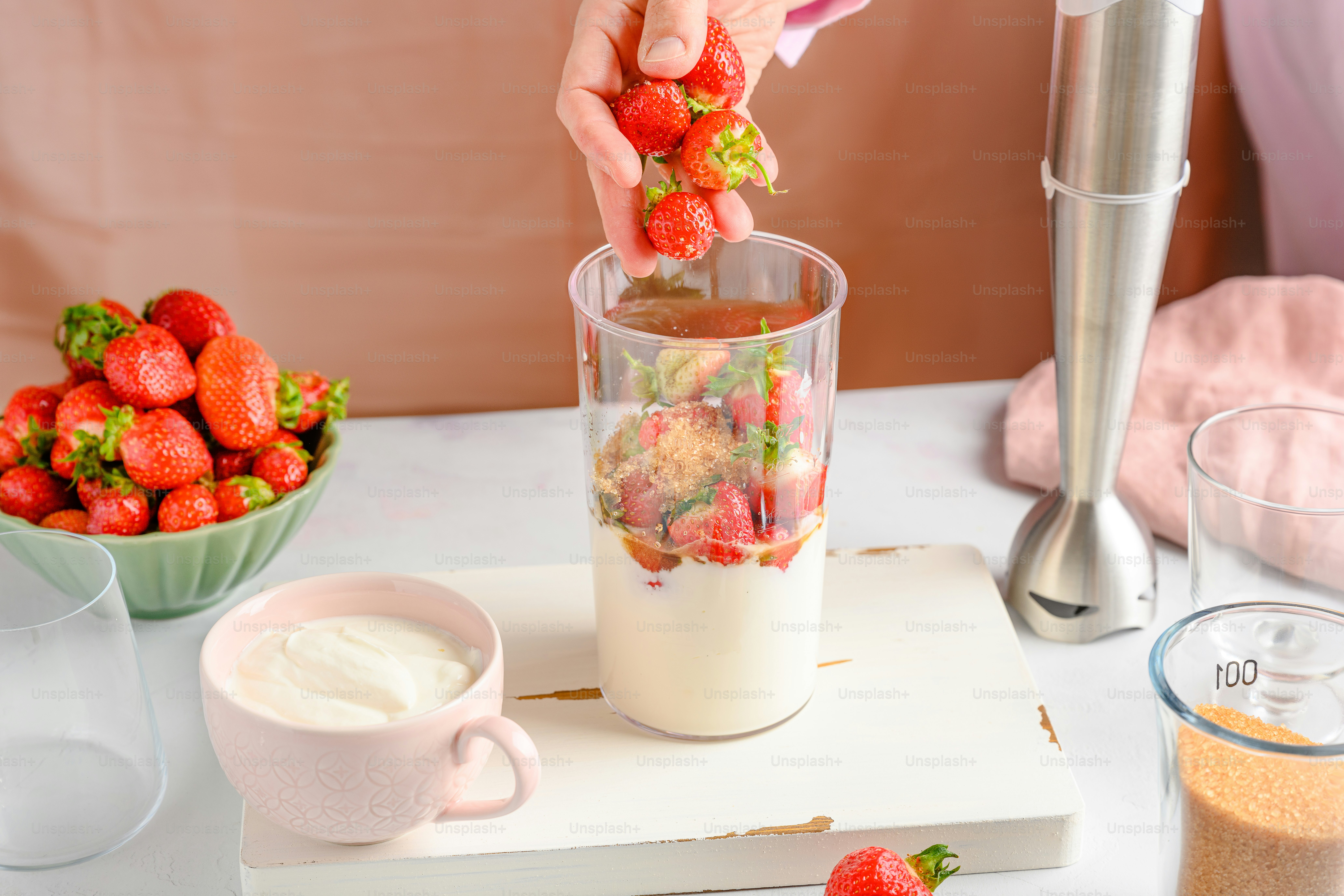 A woman making a smoothie with strawberries in a blender photo – Food ...