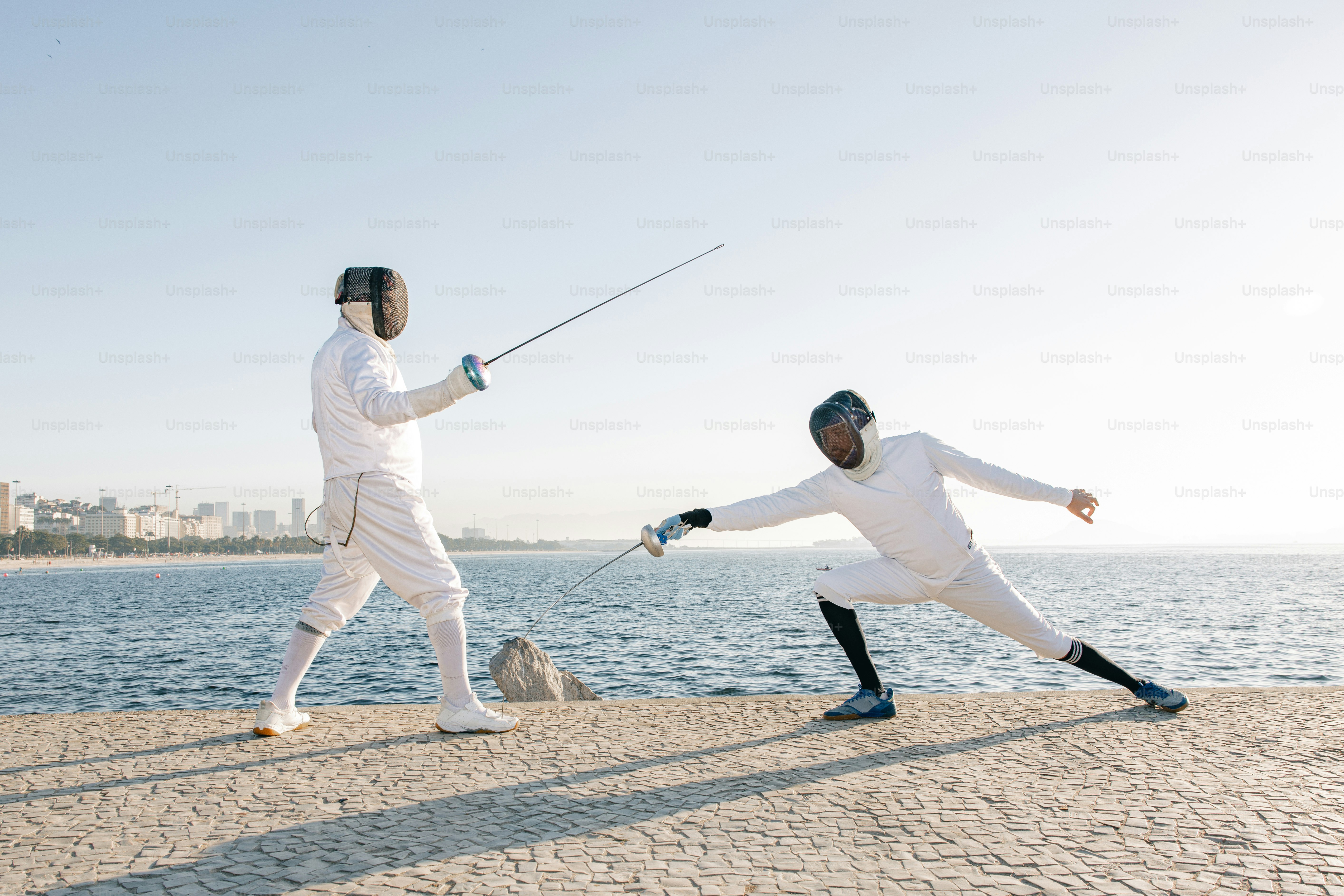 Two men in white fencing suits on a beach photo – Sword Image on Unsplash