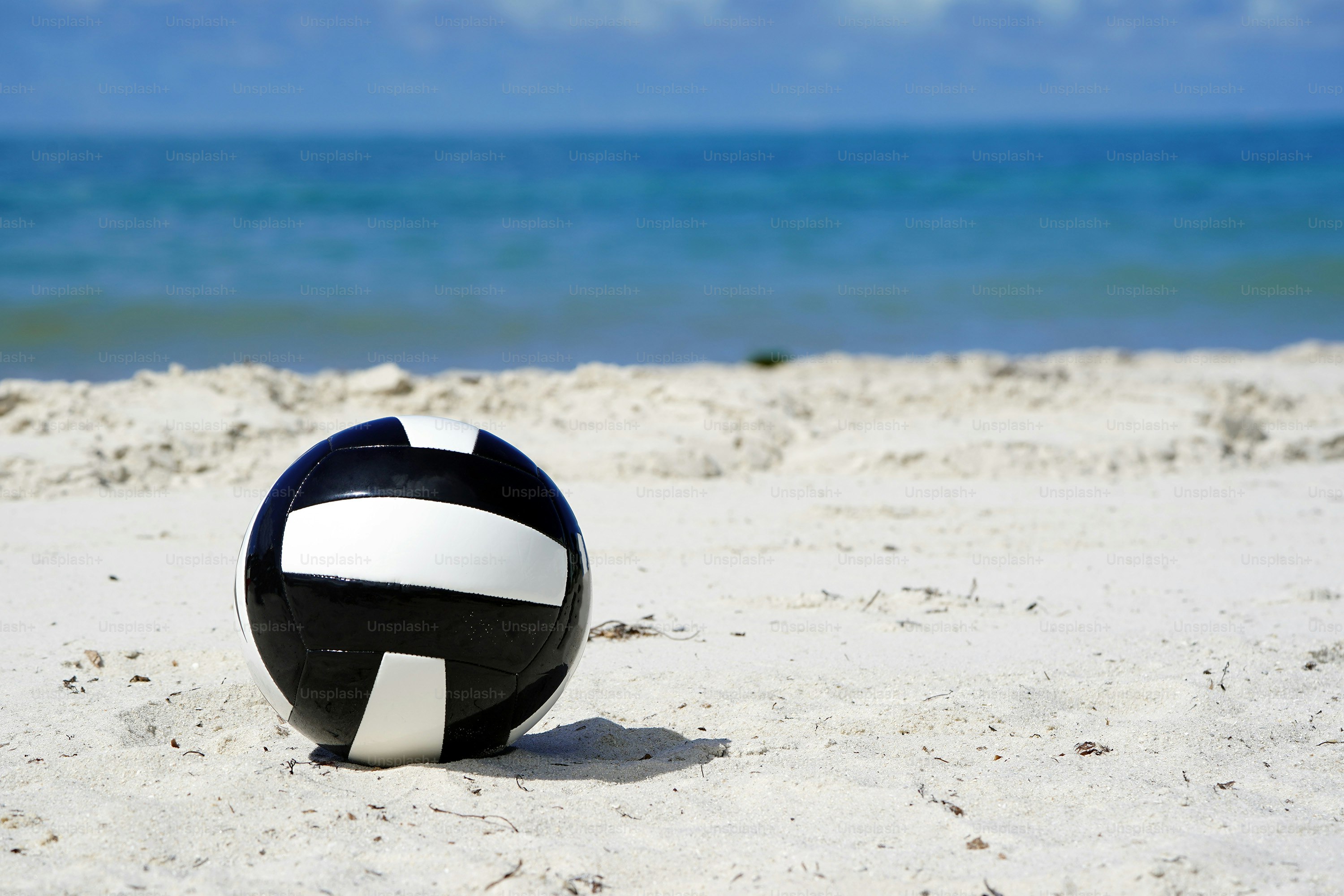 A white volleyball sitting on top of a sandy beach photo – Soccer ball ...