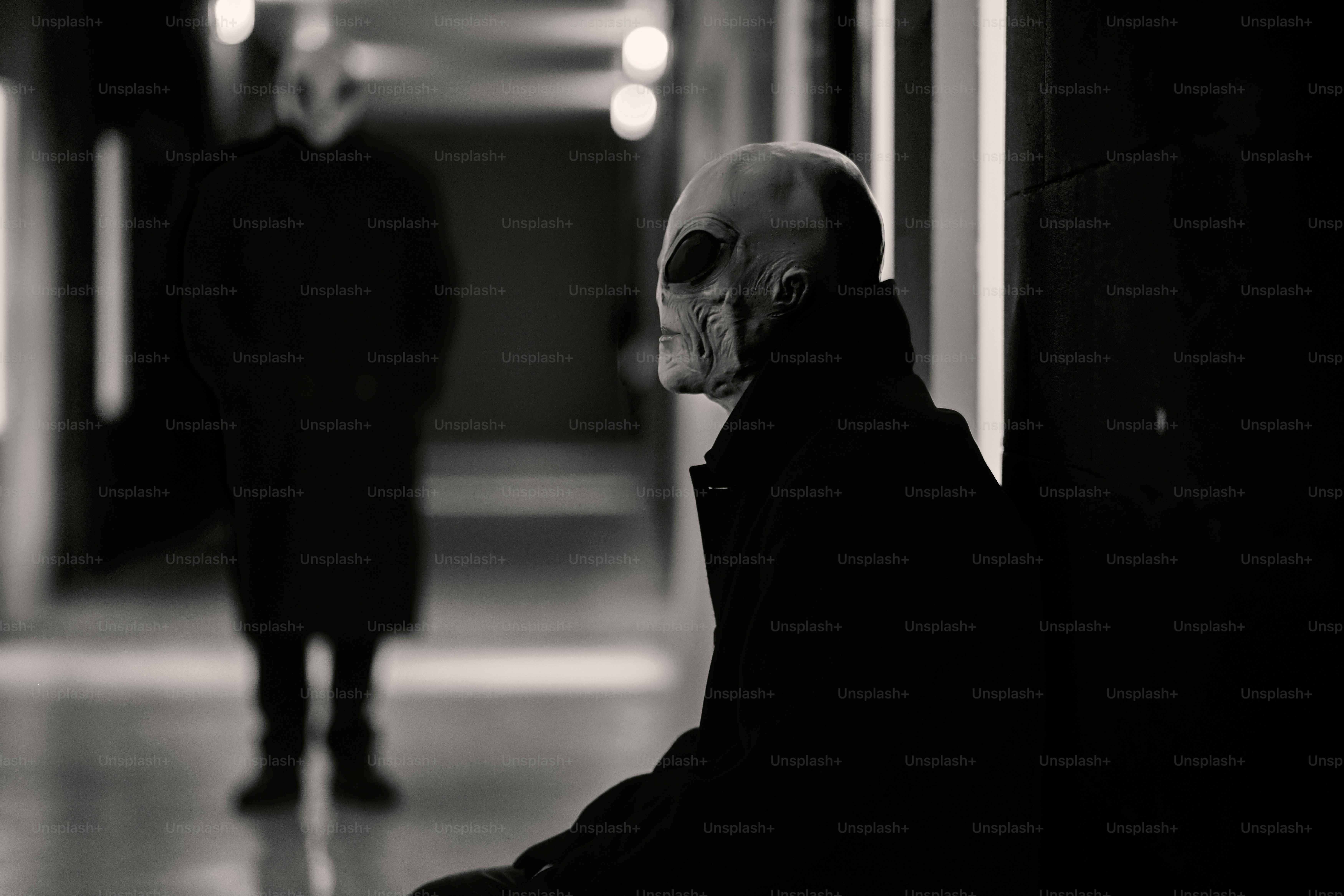 A person sitting in a hallway with a creepy mask on photo – Aliens ...