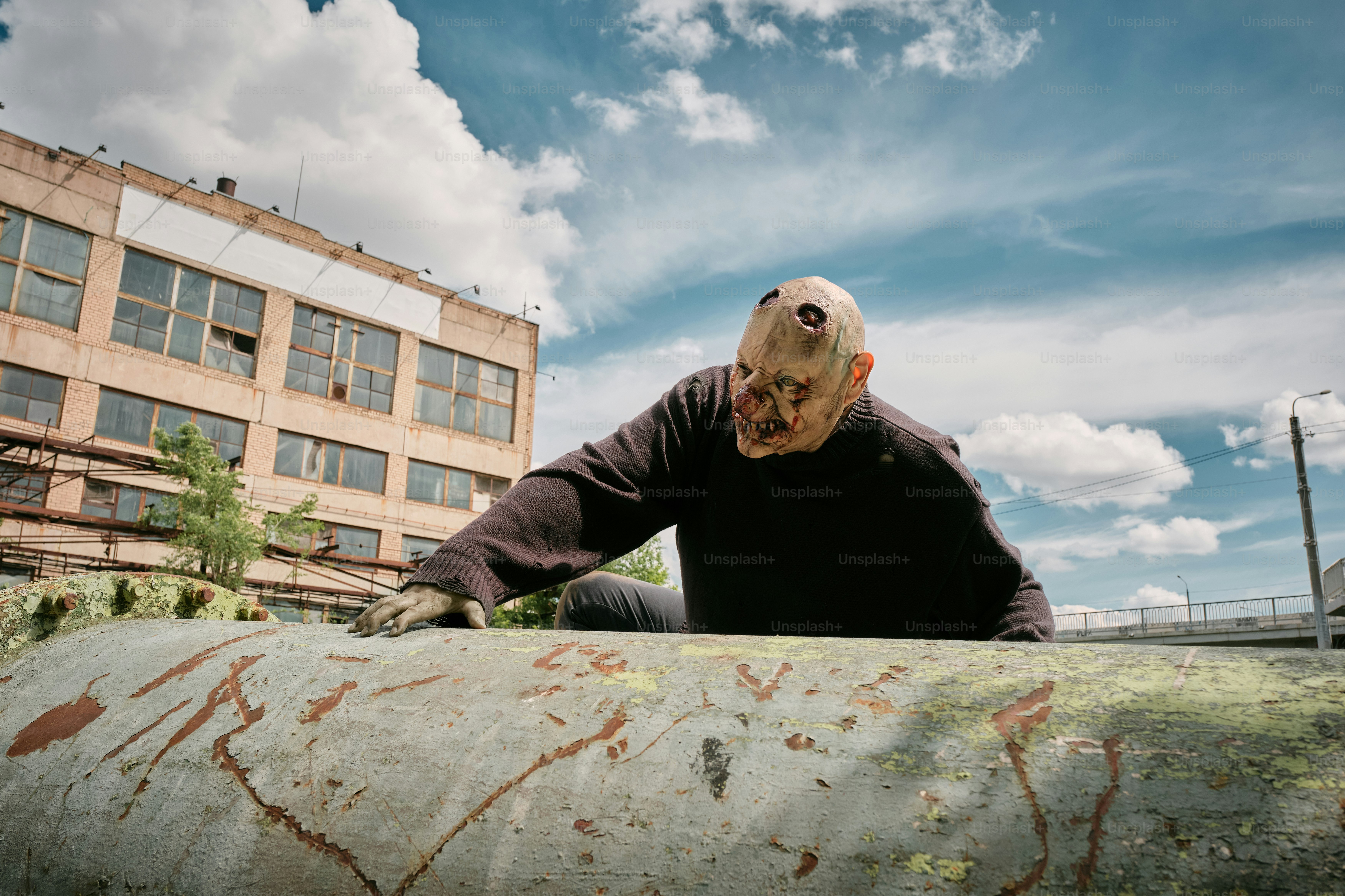 A man wearing a mask leaning on a large pipe photo – Zombie apocalypse ...